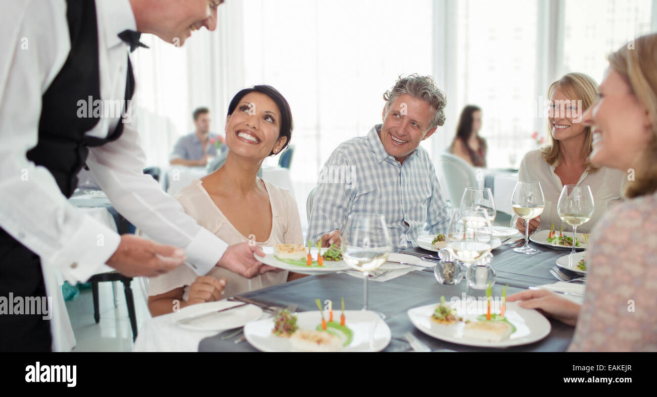 Waiter serving fancy dish to woman sitting at restaurant table Stock ...