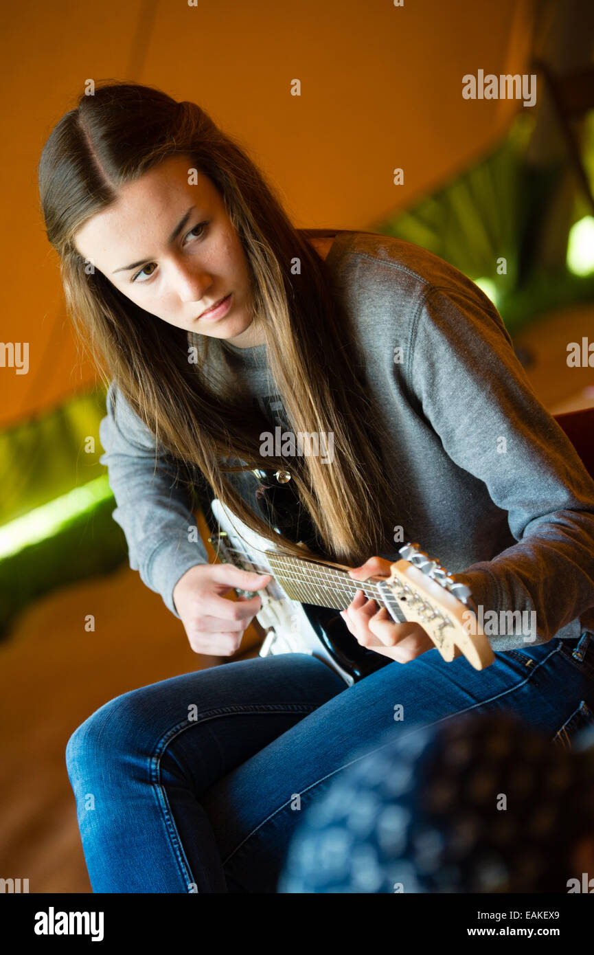 A teenage girl learning to play electric guitar at a lesson class ...