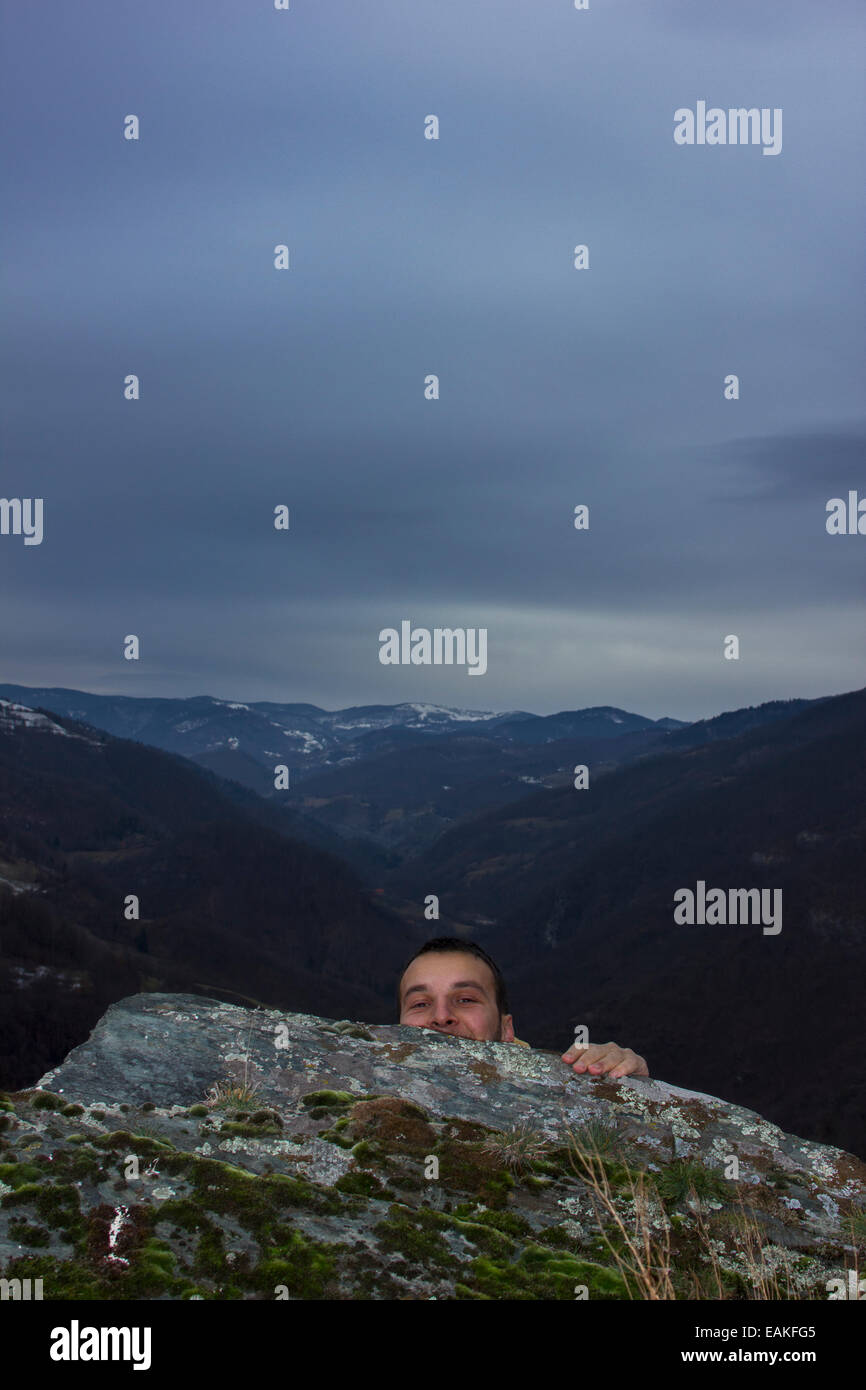 Hikers hiding behind the edge of the cliff with the valley in the ...
