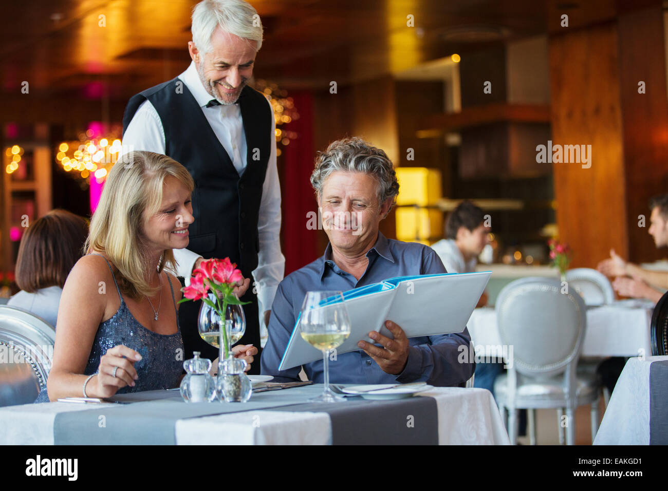 Man ordering meal at fancy restaurant table, waiter standing behind ...