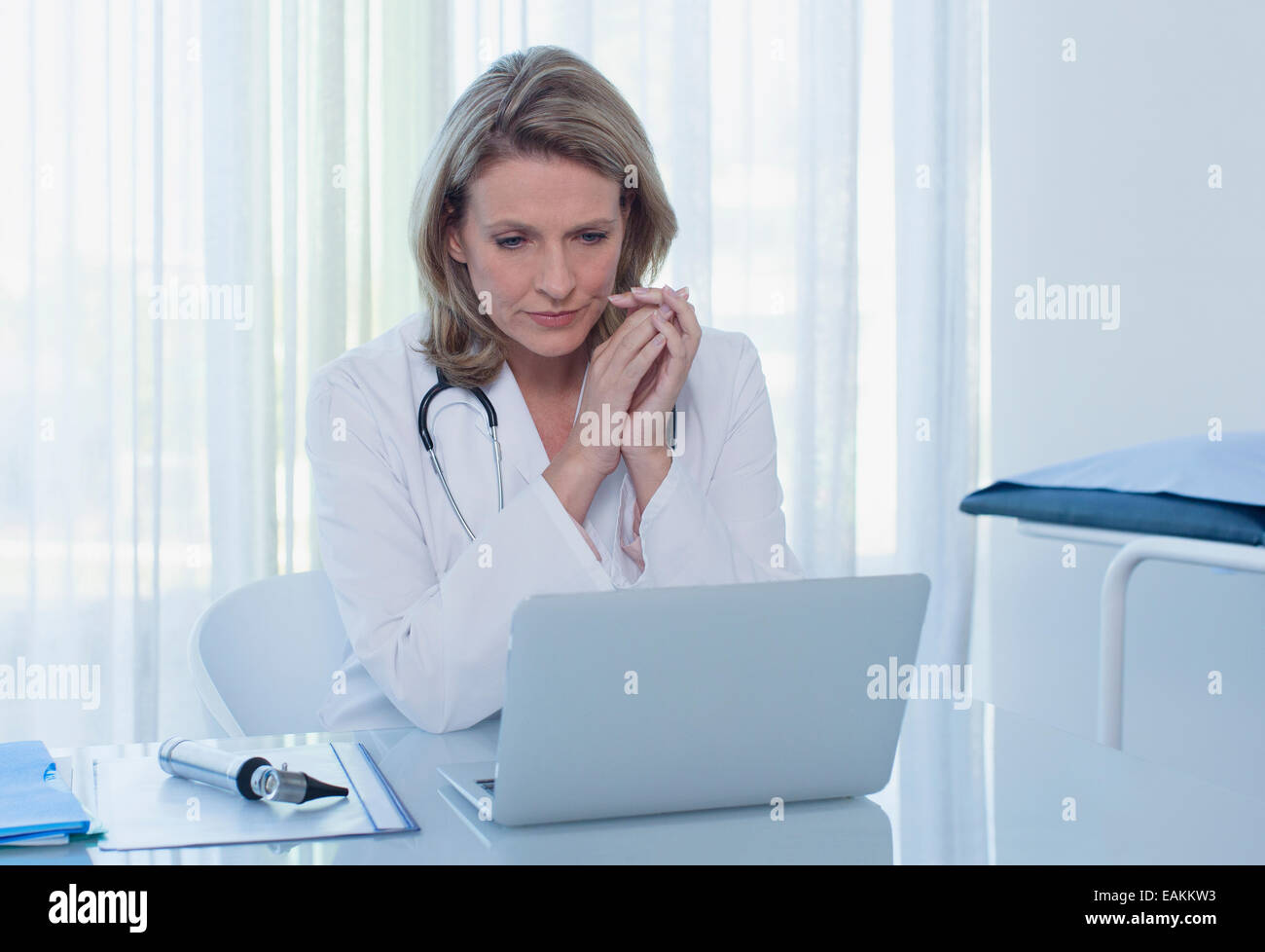 Female doctor sitting at desk with laptop in office Stock Photo - Alamy