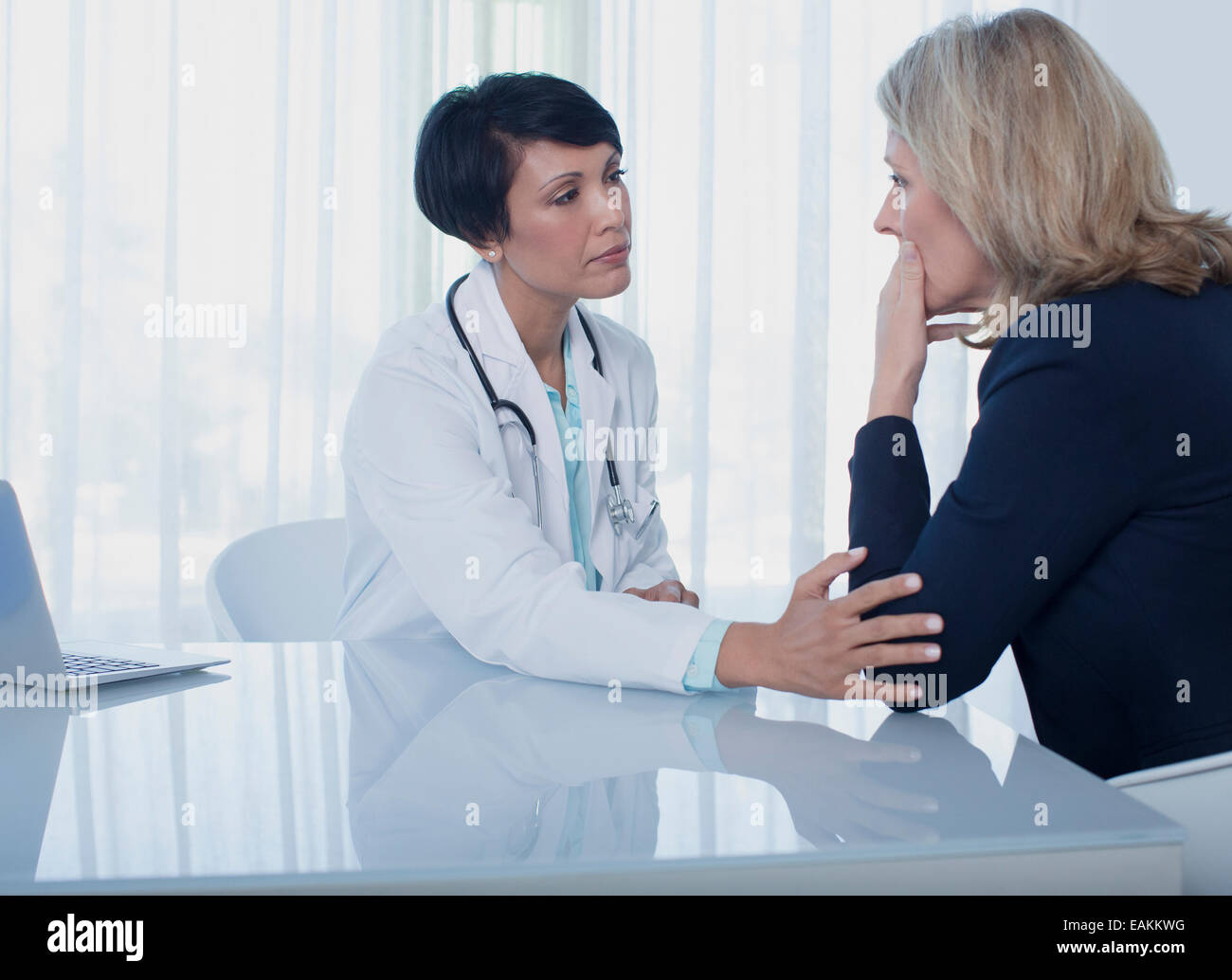 Female doctor consoling sad woman at desk in office Stock Photo - Alamy