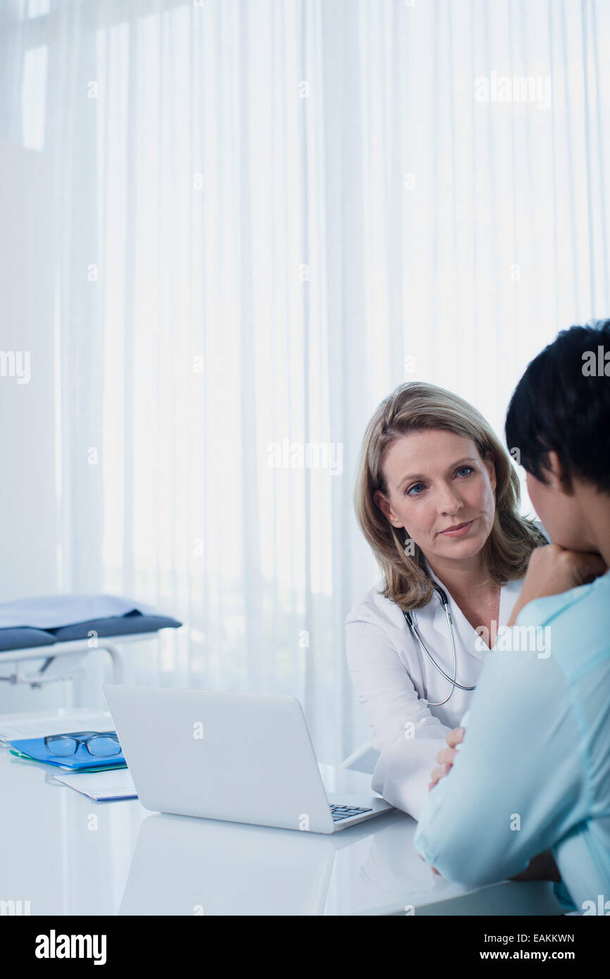 Female doctor talking to woman at desk in office Stock Photo - Alamy