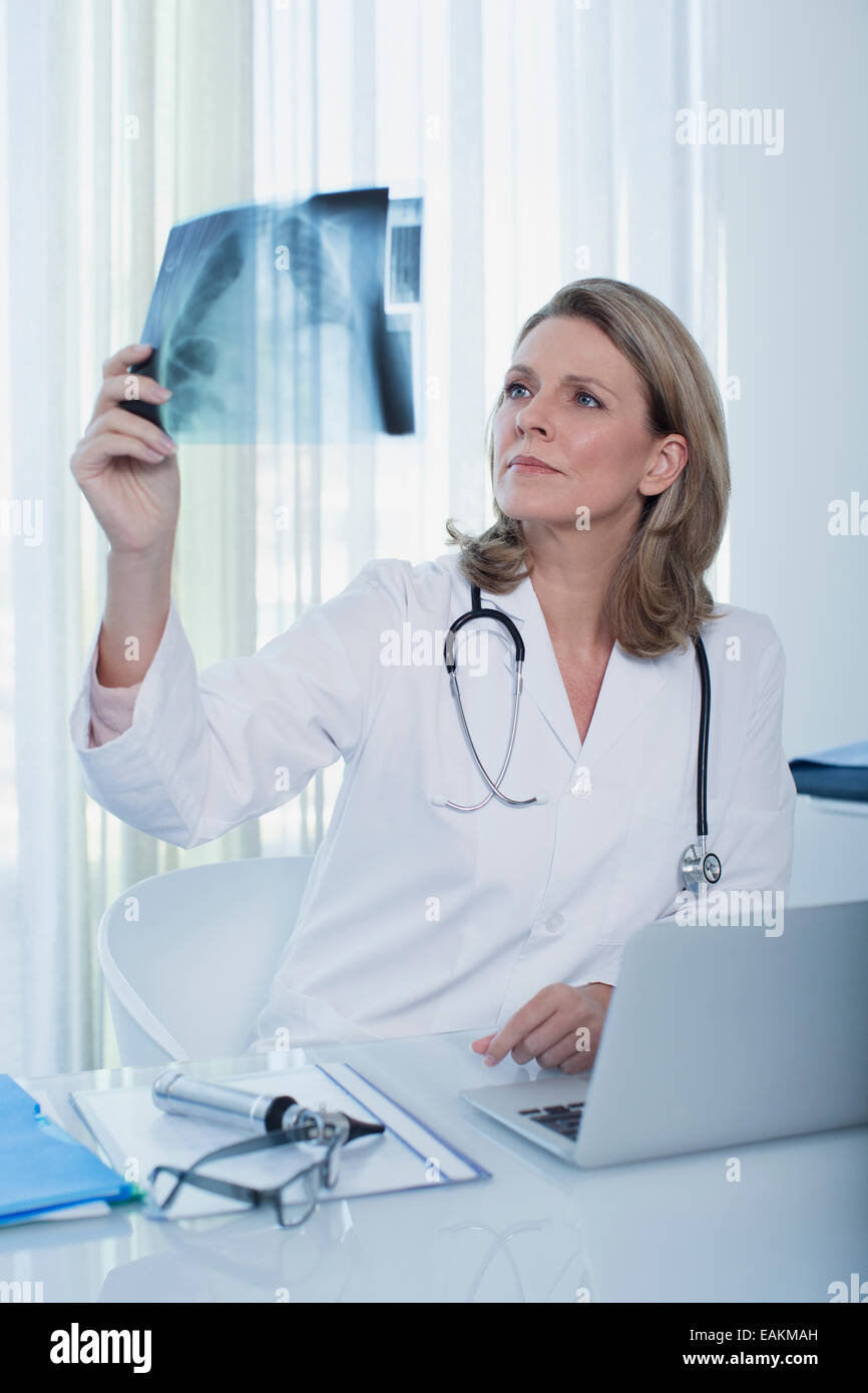 Female doctor looking at x-ray at desk with laptop in office Stock ...
