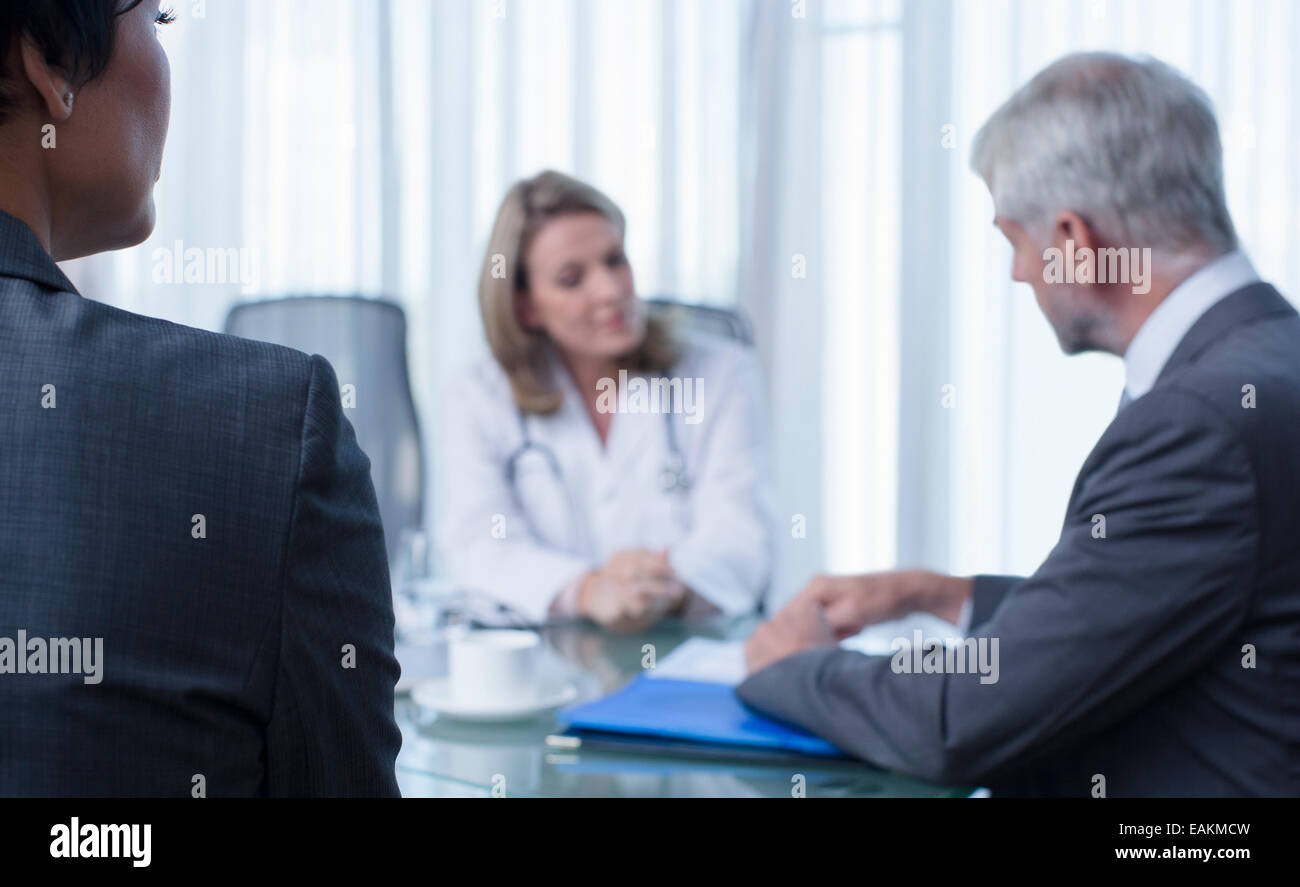 Female doctor, man and woman talking at table in conference room Stock ...