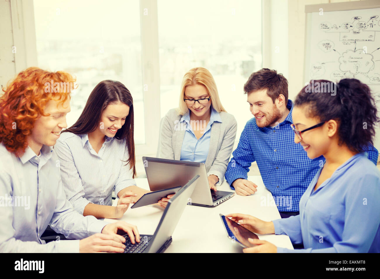 smiling team with laptop and table pc computers Stock Photo - Alamy