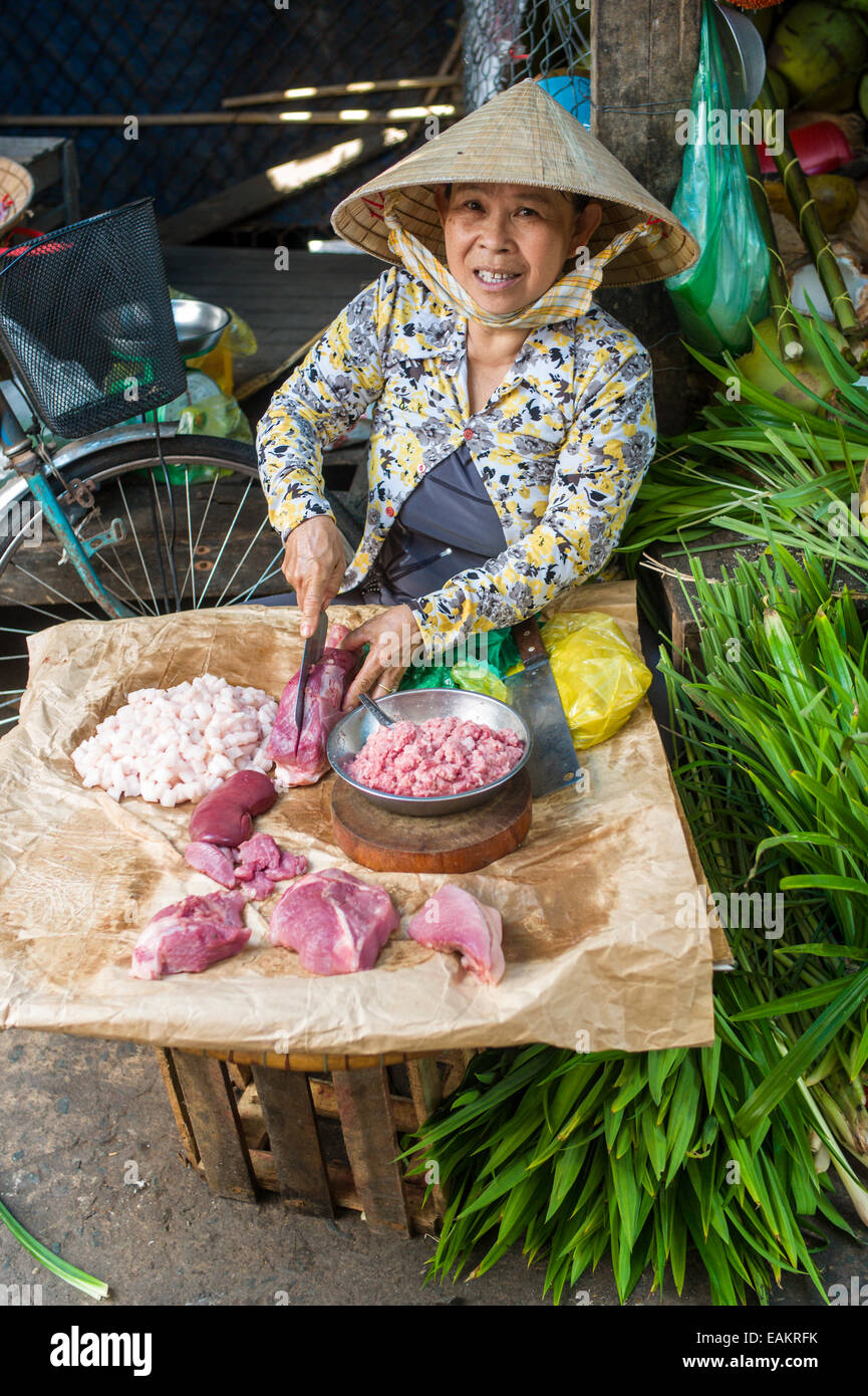 Vietnam vendor in traditional conical hat chopping up meat for sale on ...