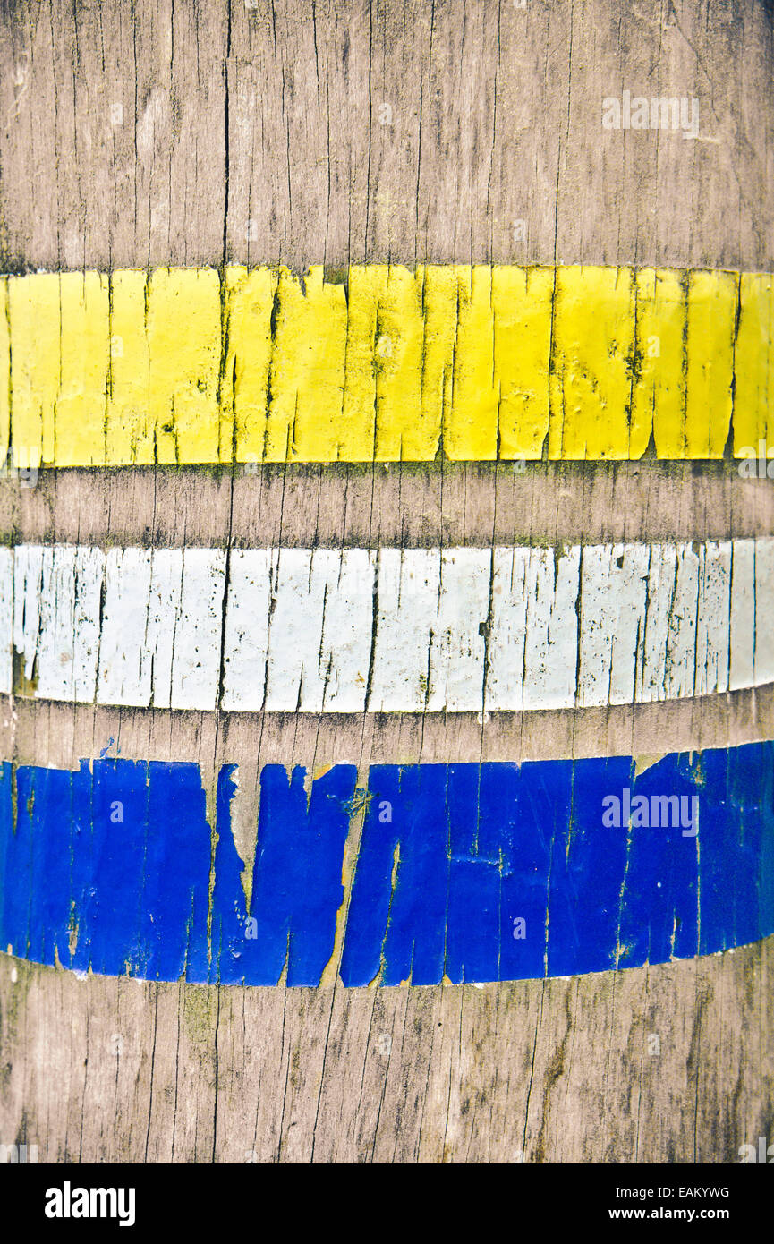 Yellow, blue and white painted stripes on a wooden post Stock Photo - Alamy