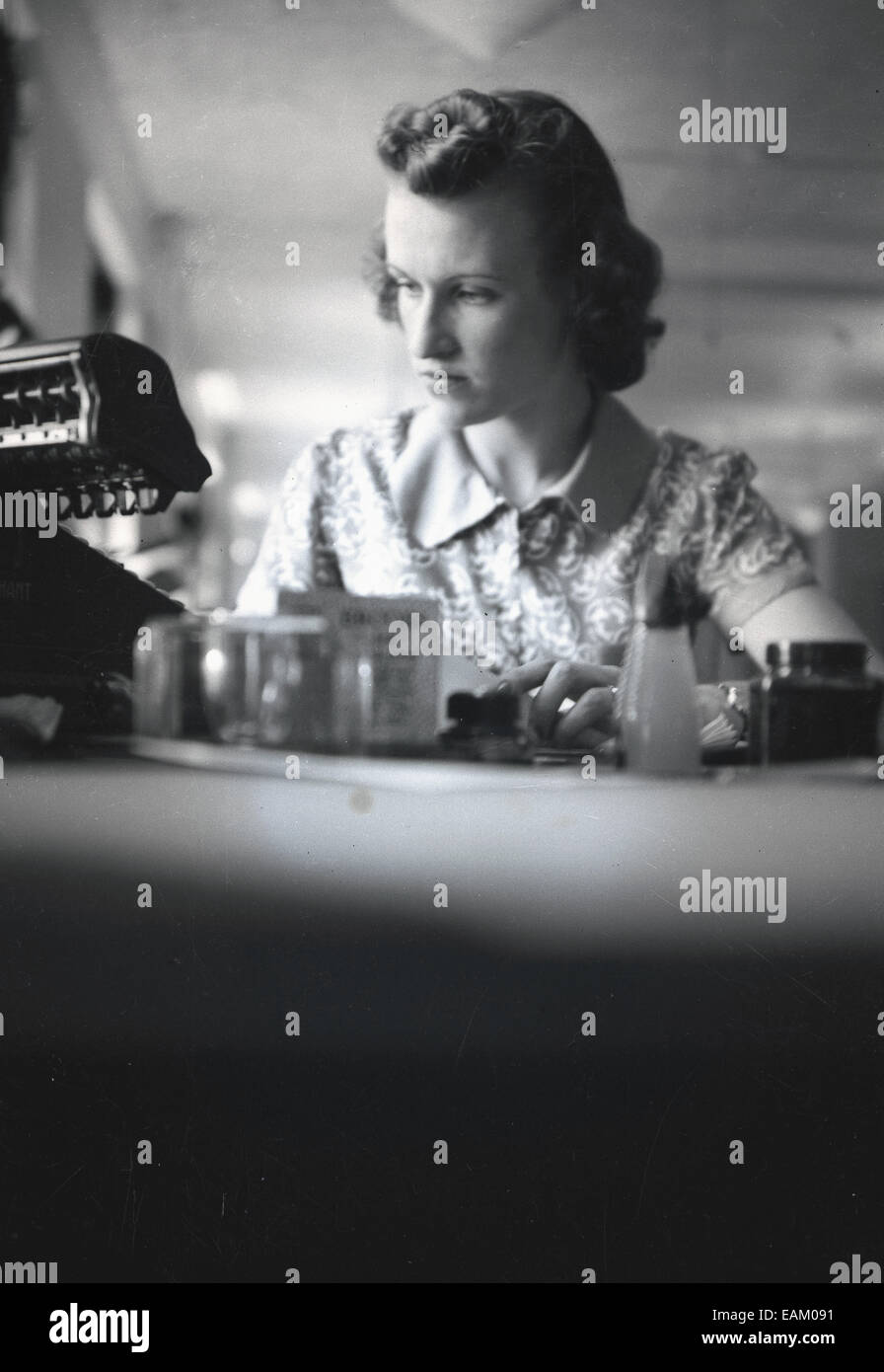 1940s, historical picture showing a young lady at a desk with a ...