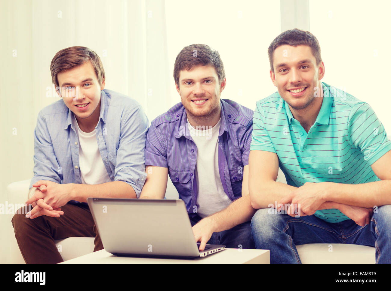 smiling friends with laptop computer at home Stock Photo - Alamy