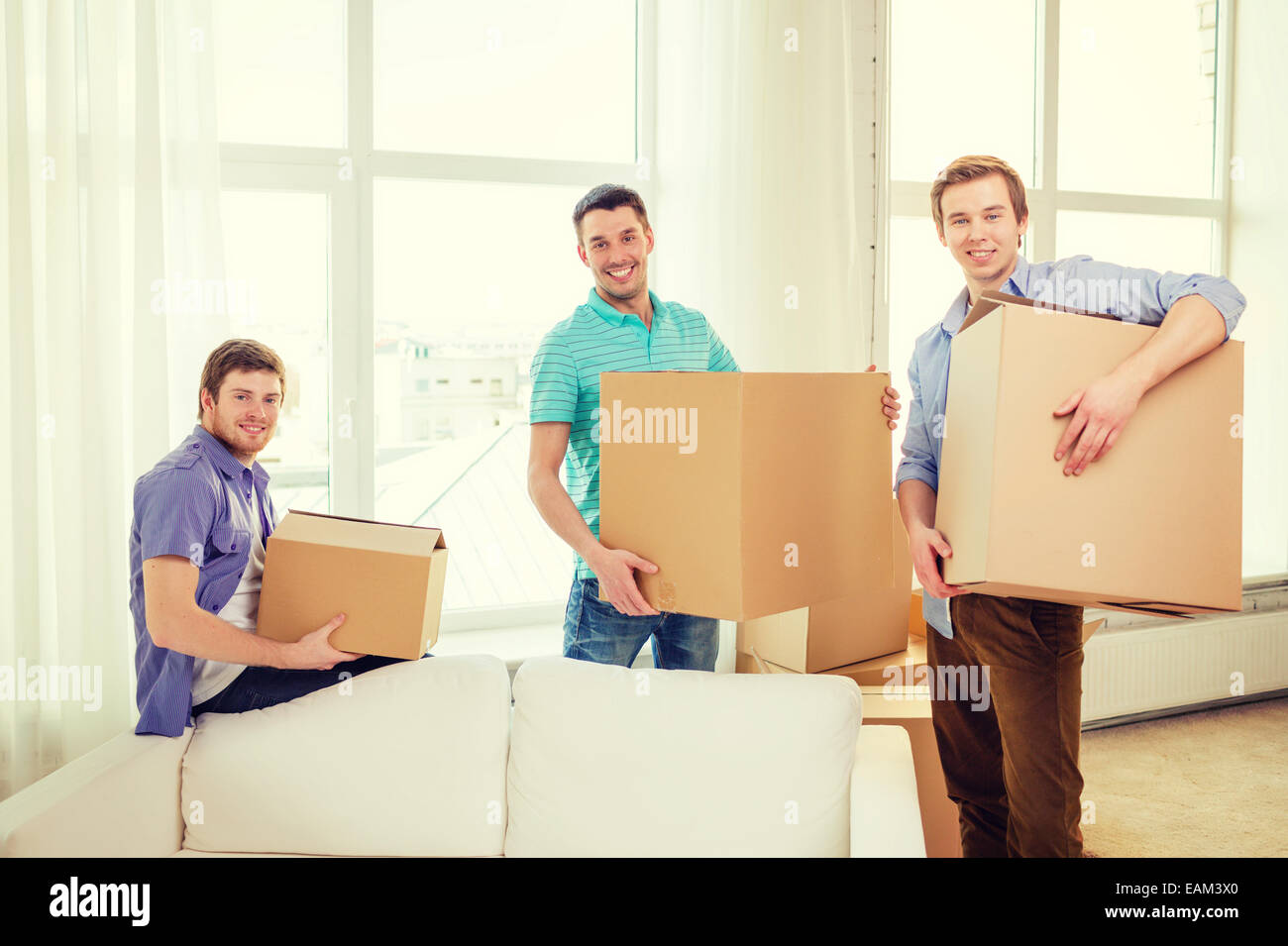 smiling male friends carrying boxes at new place Stock Photo - Alamy