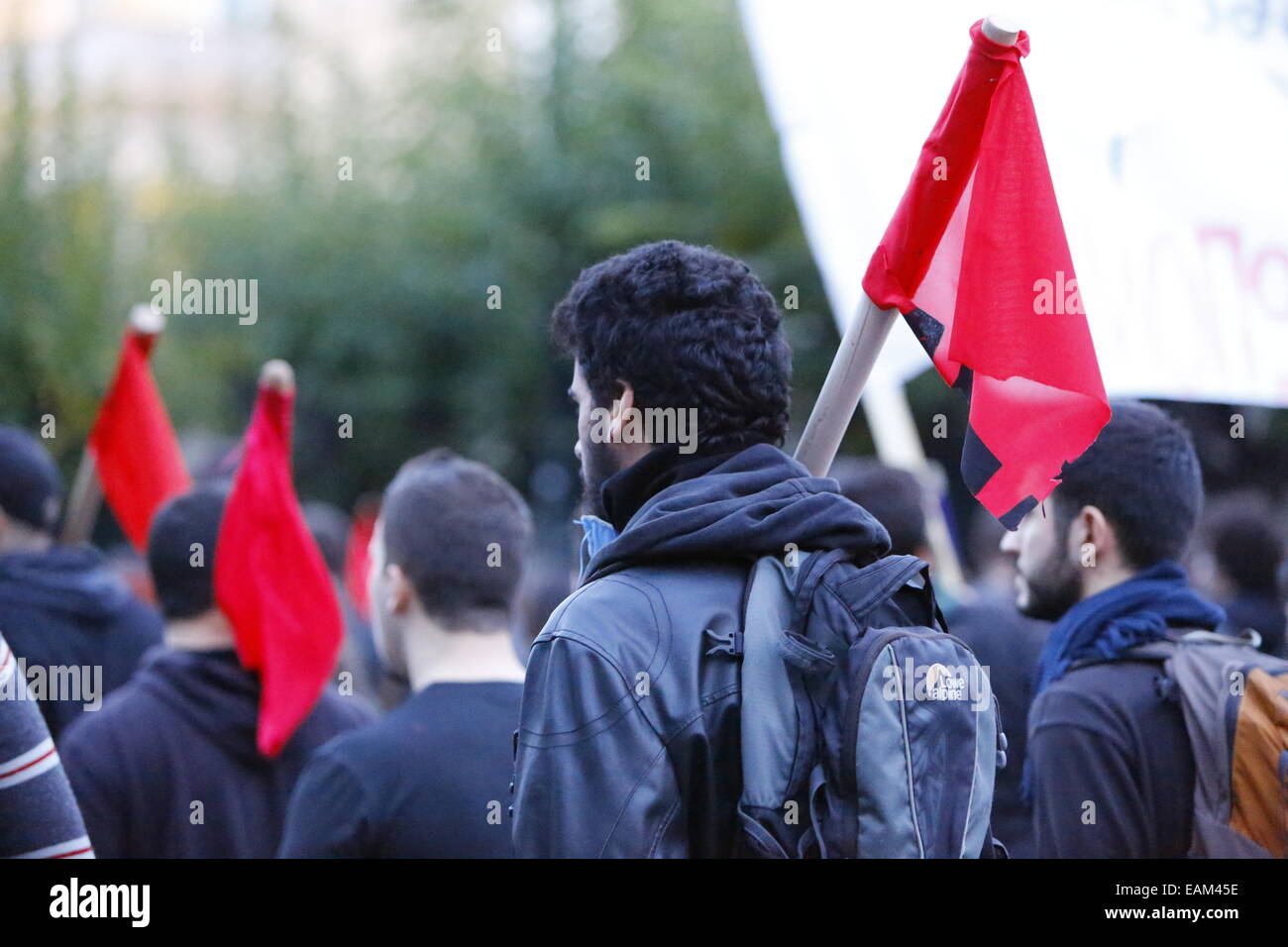 A protester marches with a red flag carried over his shoulder ...