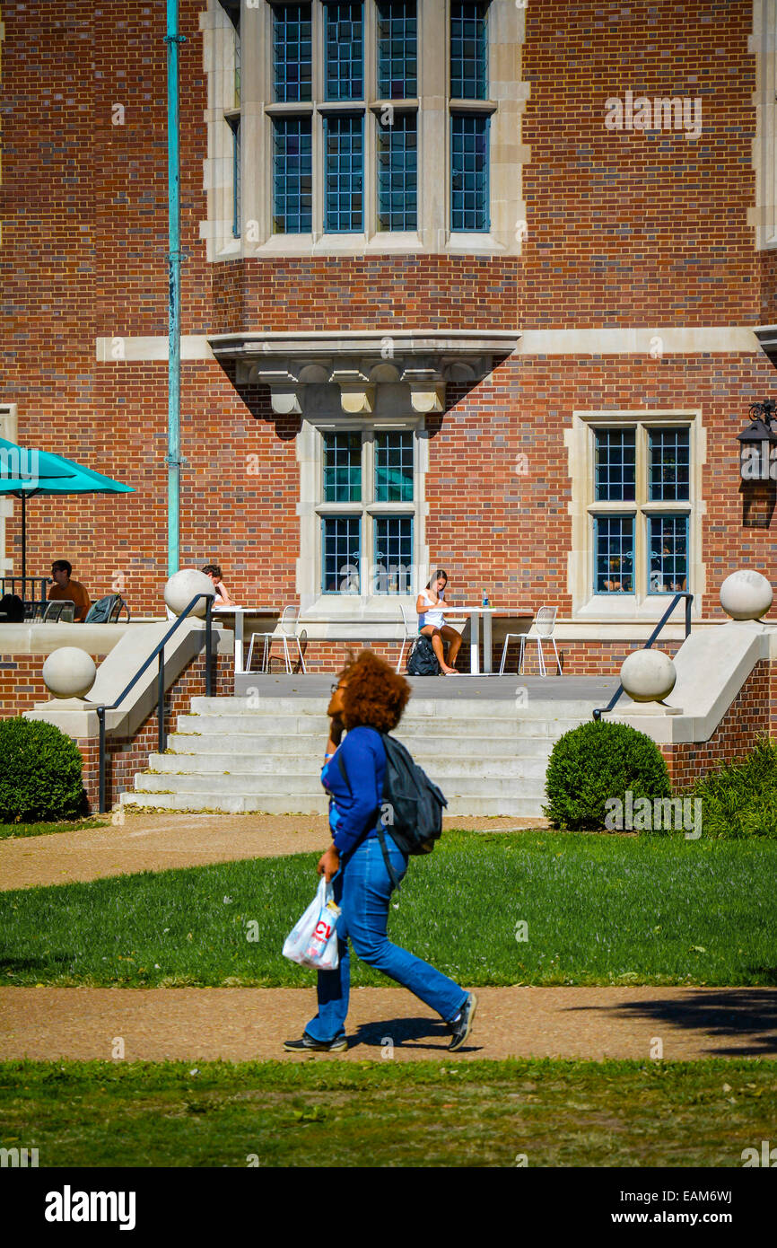 A student of color walks in front of the Alumni Hall while other ...