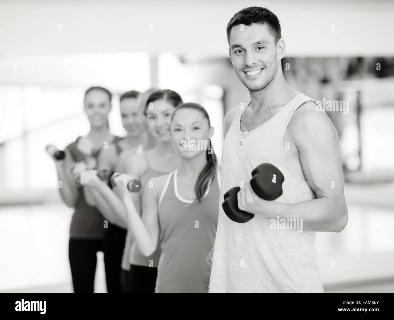 group of smiling people with dumbbells in the gym Stock Photo - Alamy