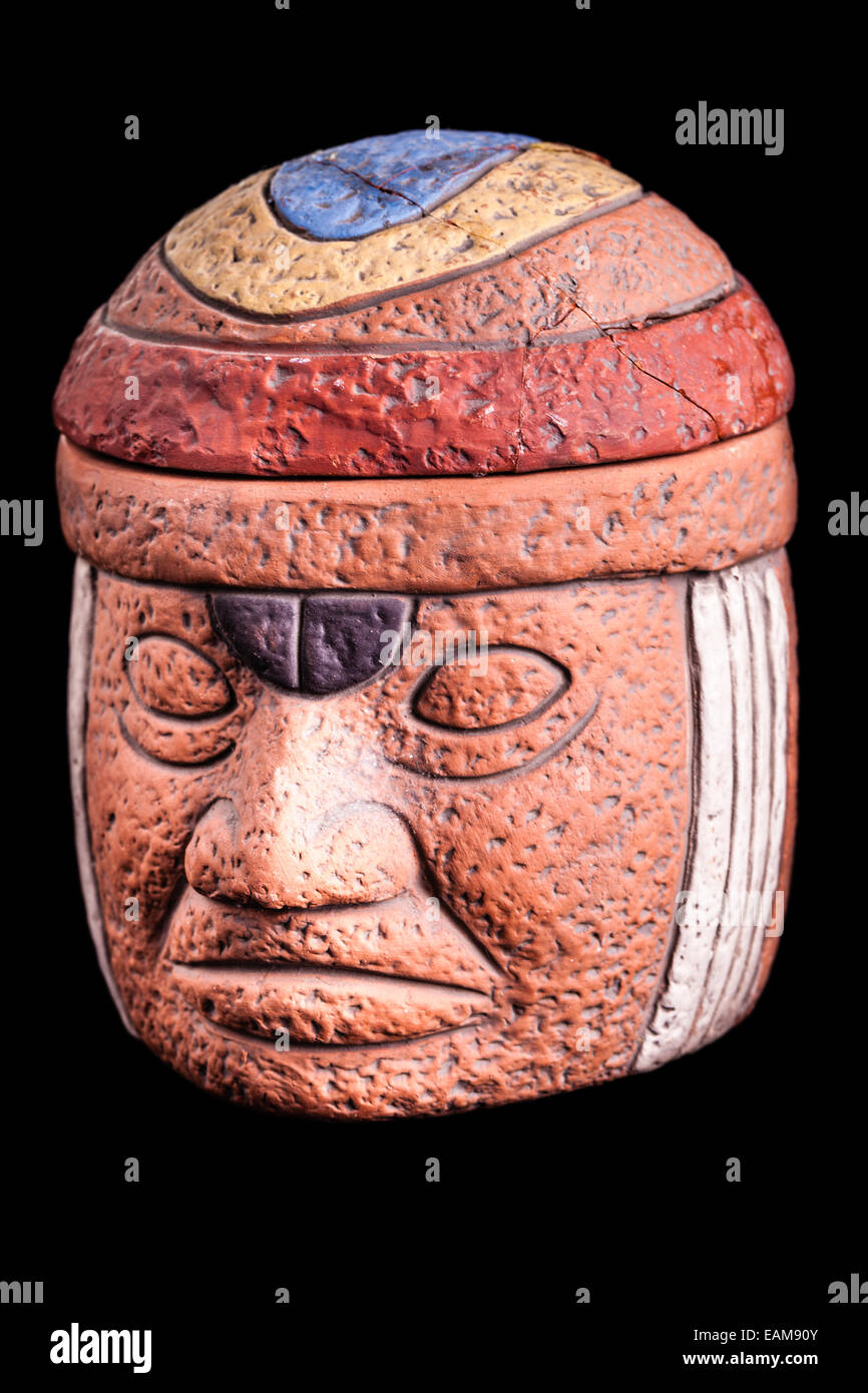 a terracotta olmec face idol souvenir isolated over a black background ...