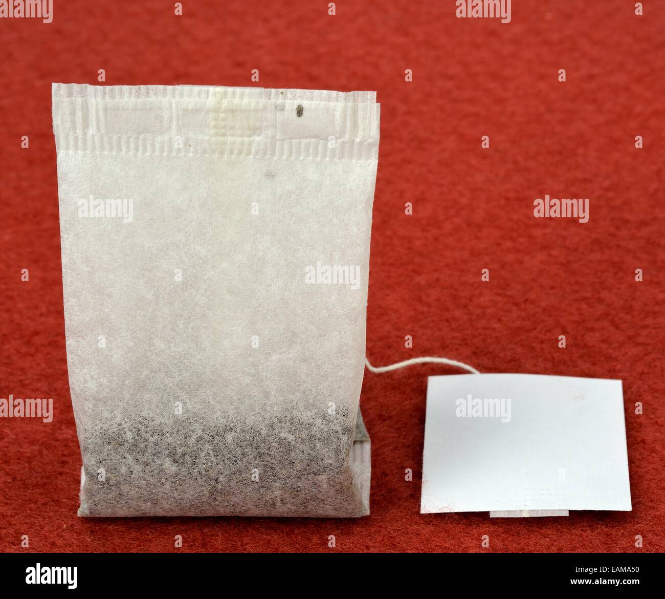 Single tea bag on a red background Stock Photo - Alamy