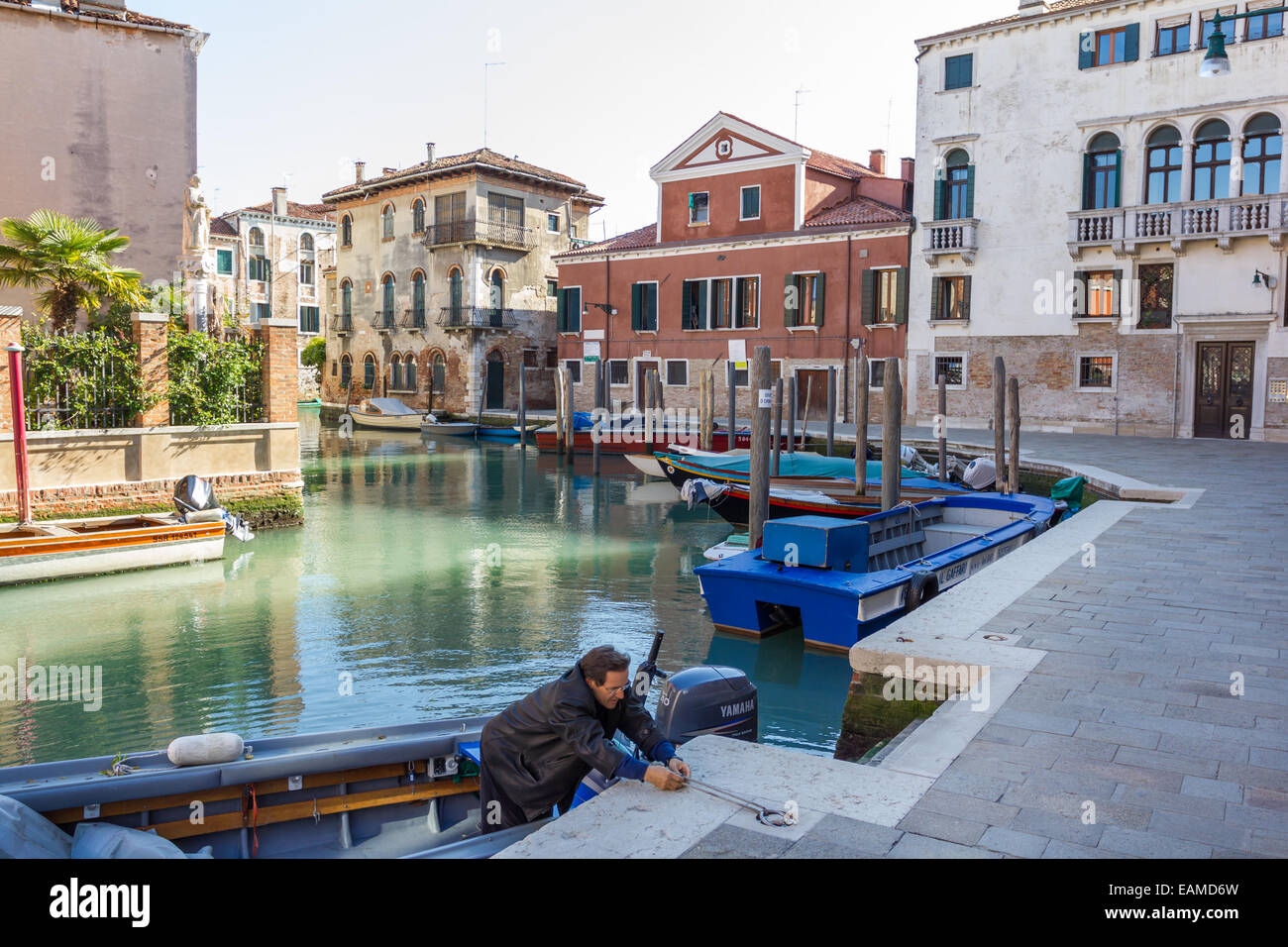 Man ties up boat on canal, Lido Venice, Italy Stock Photo - Alamy
