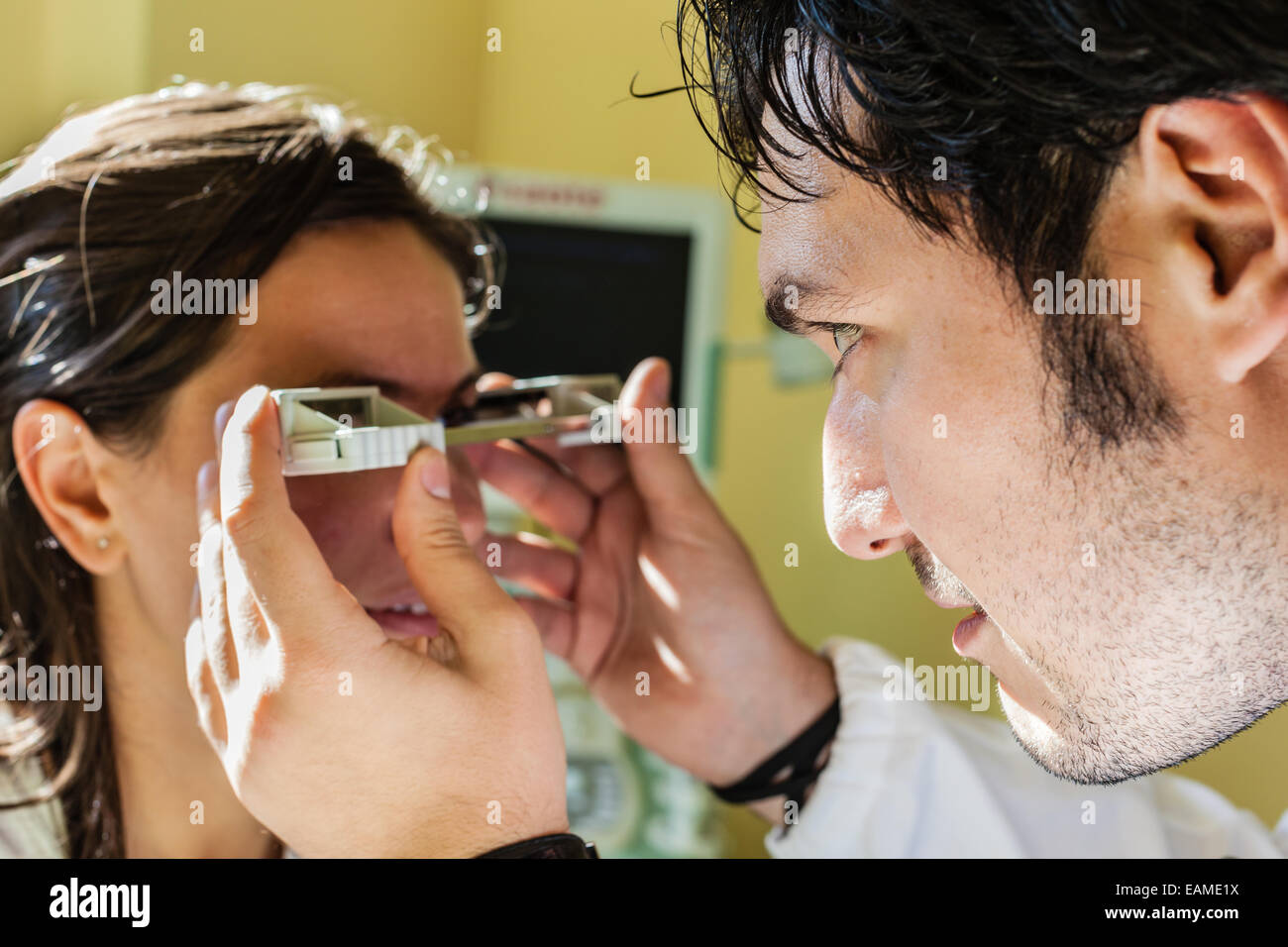 a young ophthalmologist using an exophthalmometer, an instrument used ...