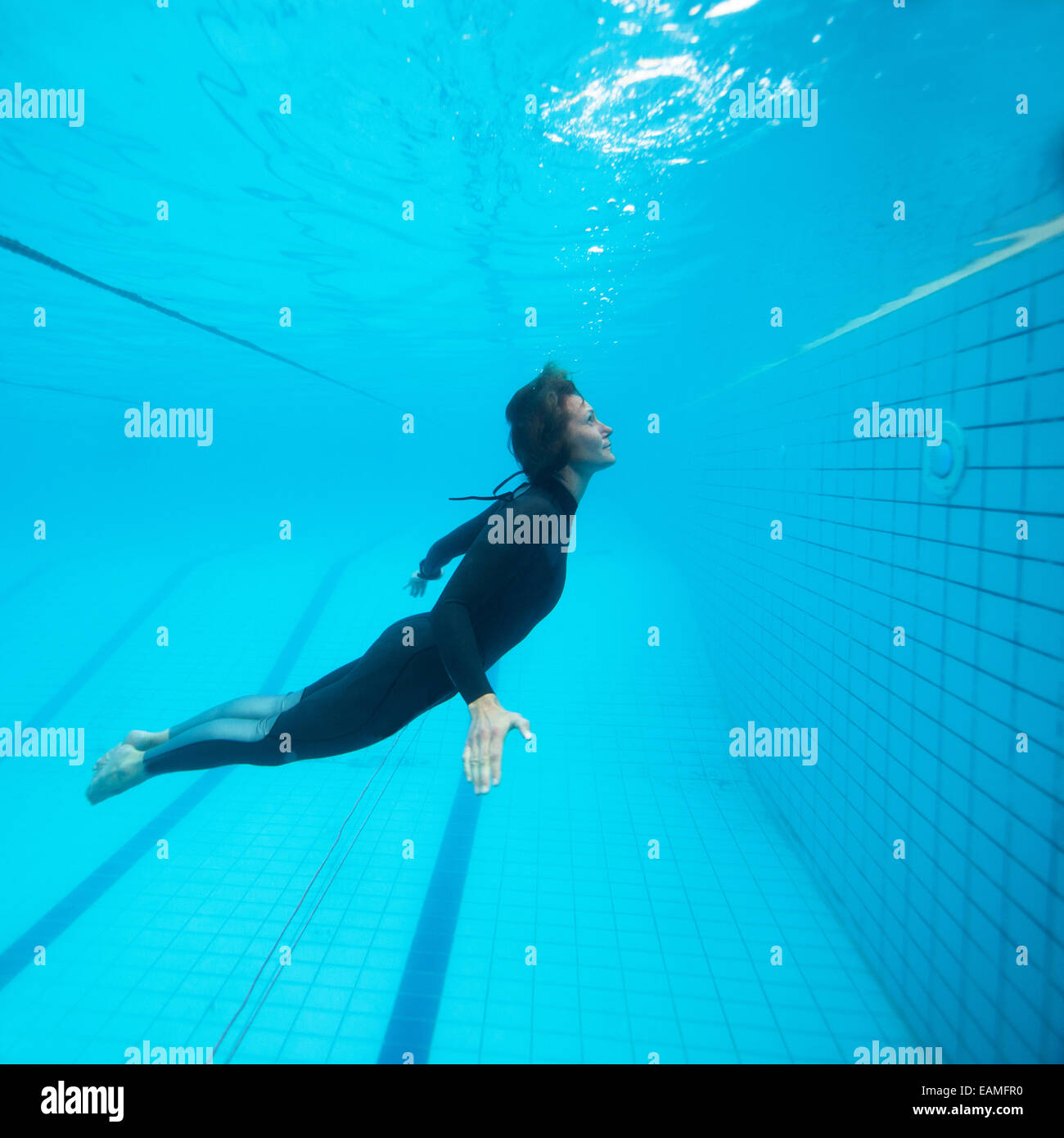 Female diver underwater in swimming pool with eyes open looking upwards ...