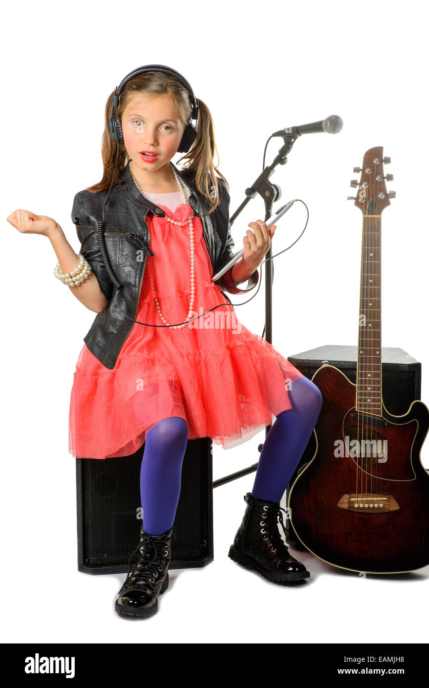a young and pretty musician is sitting on loudspeakers with guitar ...