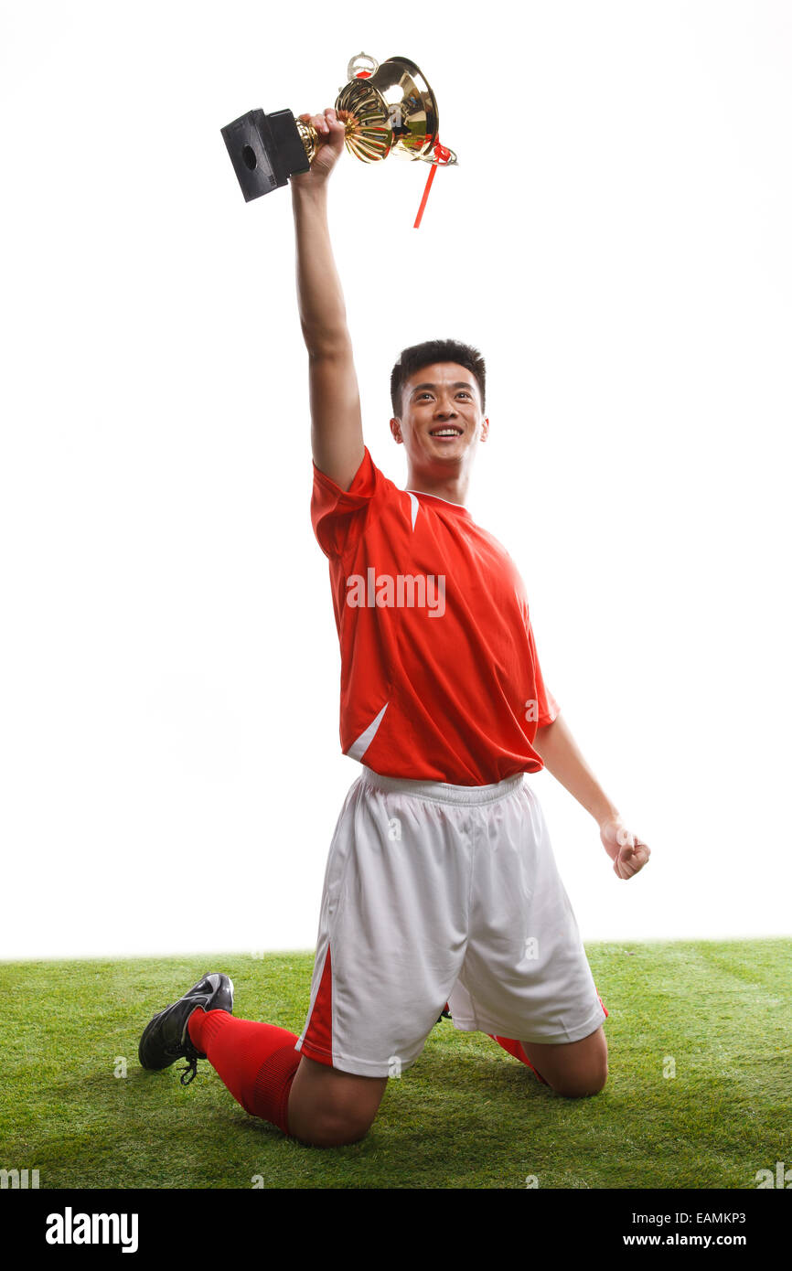 A football player knelt down on the grass holding the cup Stock Photo ...