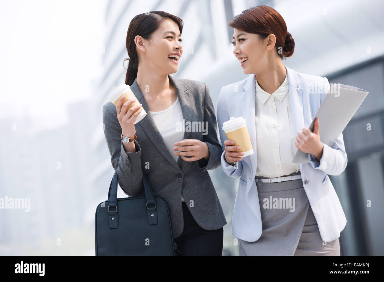 Two business lady holding a coffee cup on the way to work Stock Photo ...