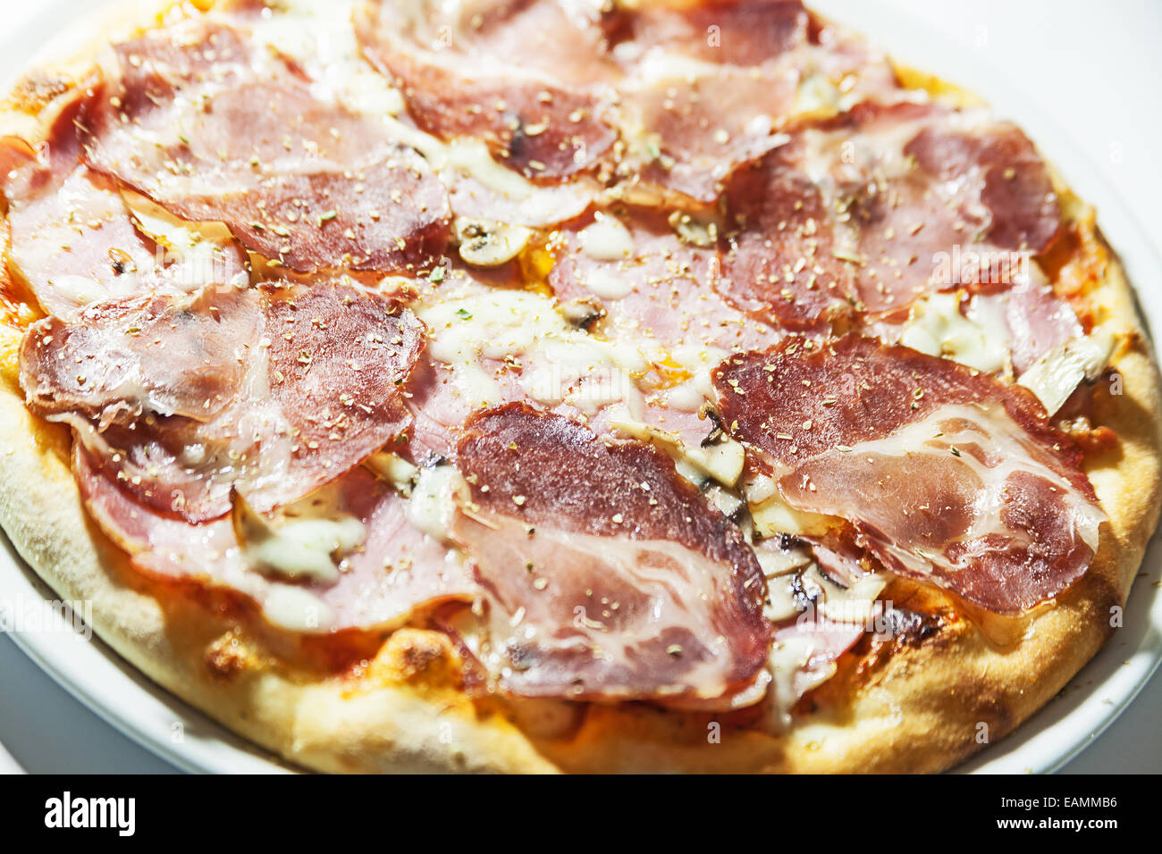 Pizza with meat and ham, served on white plate Stock Photo - Alamy