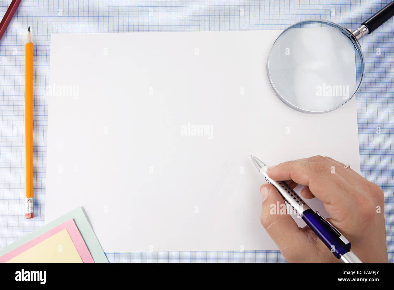 male hand writing by pen and magnifying glass on graph grid paper Stock ...