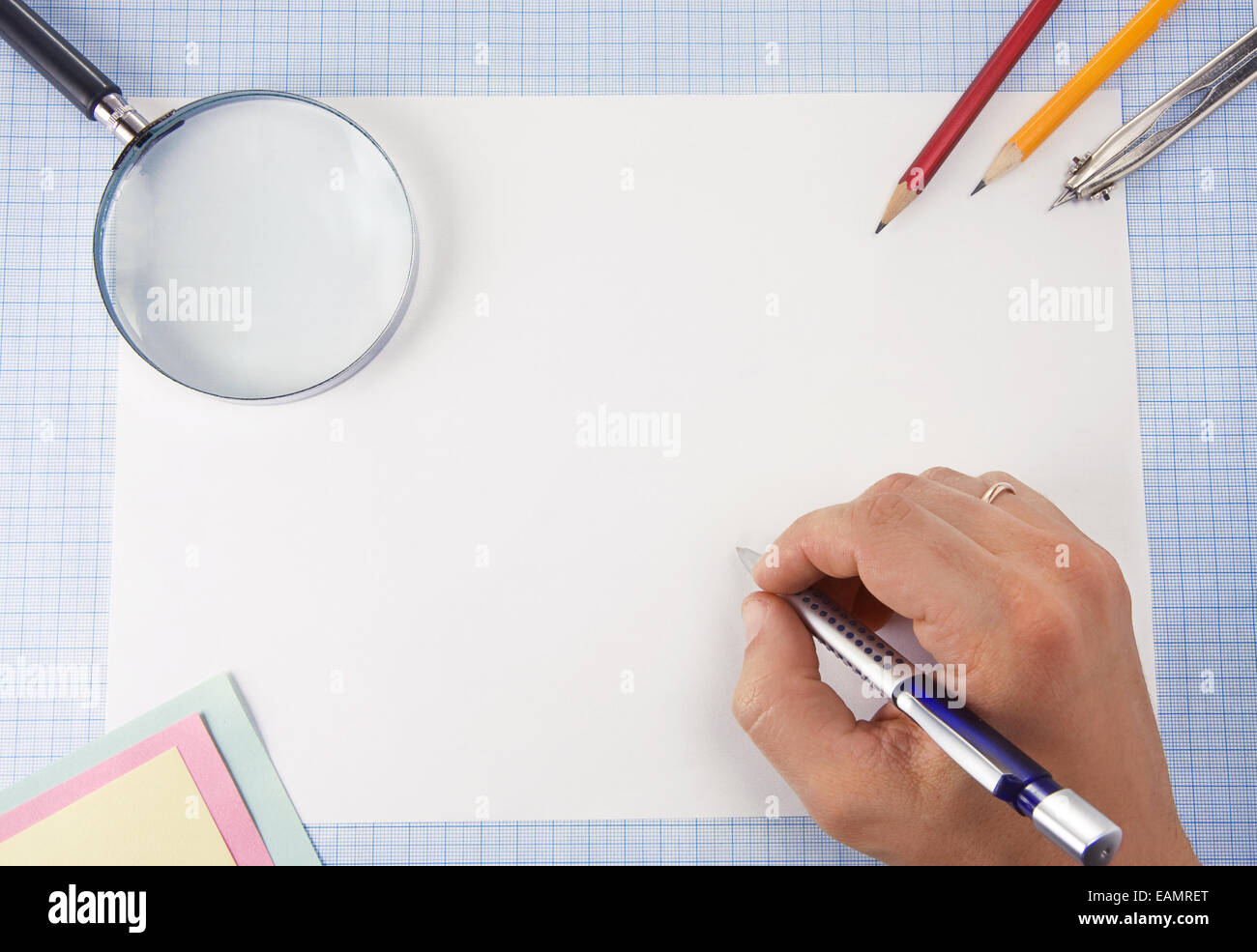 male hand writing by pen and magnifying glass on graph grid paper Stock ...
