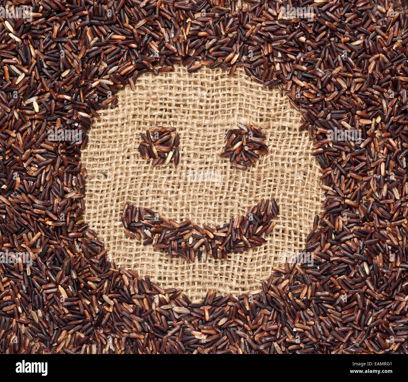 Red rice forming a smiley face on burlap fabric Stock Photo - Alamy
