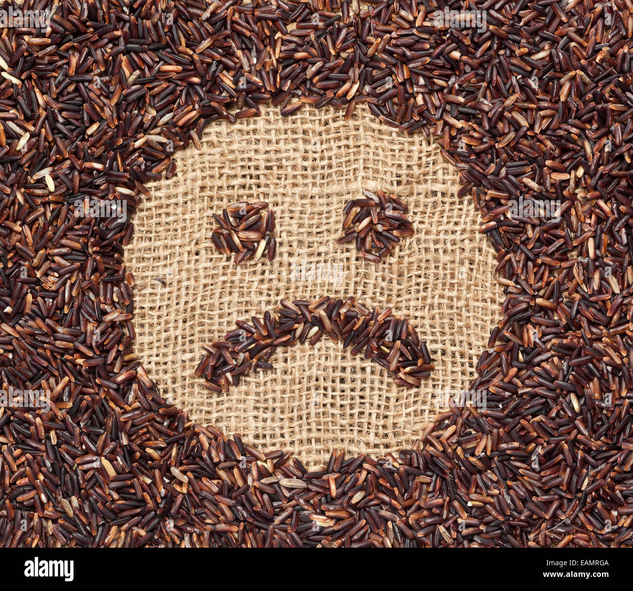 Red rice forming a sad face on burlap fabric Stock Photo - Alamy