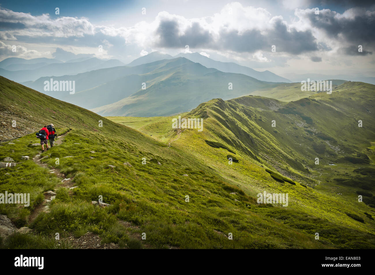 Two hikers walking on a mountain path, on a ridge Stock Photo - Alamy