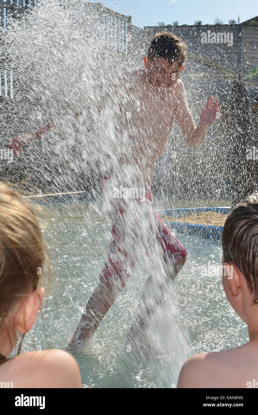 A tween boy running through a shower jet of water at a water park ...