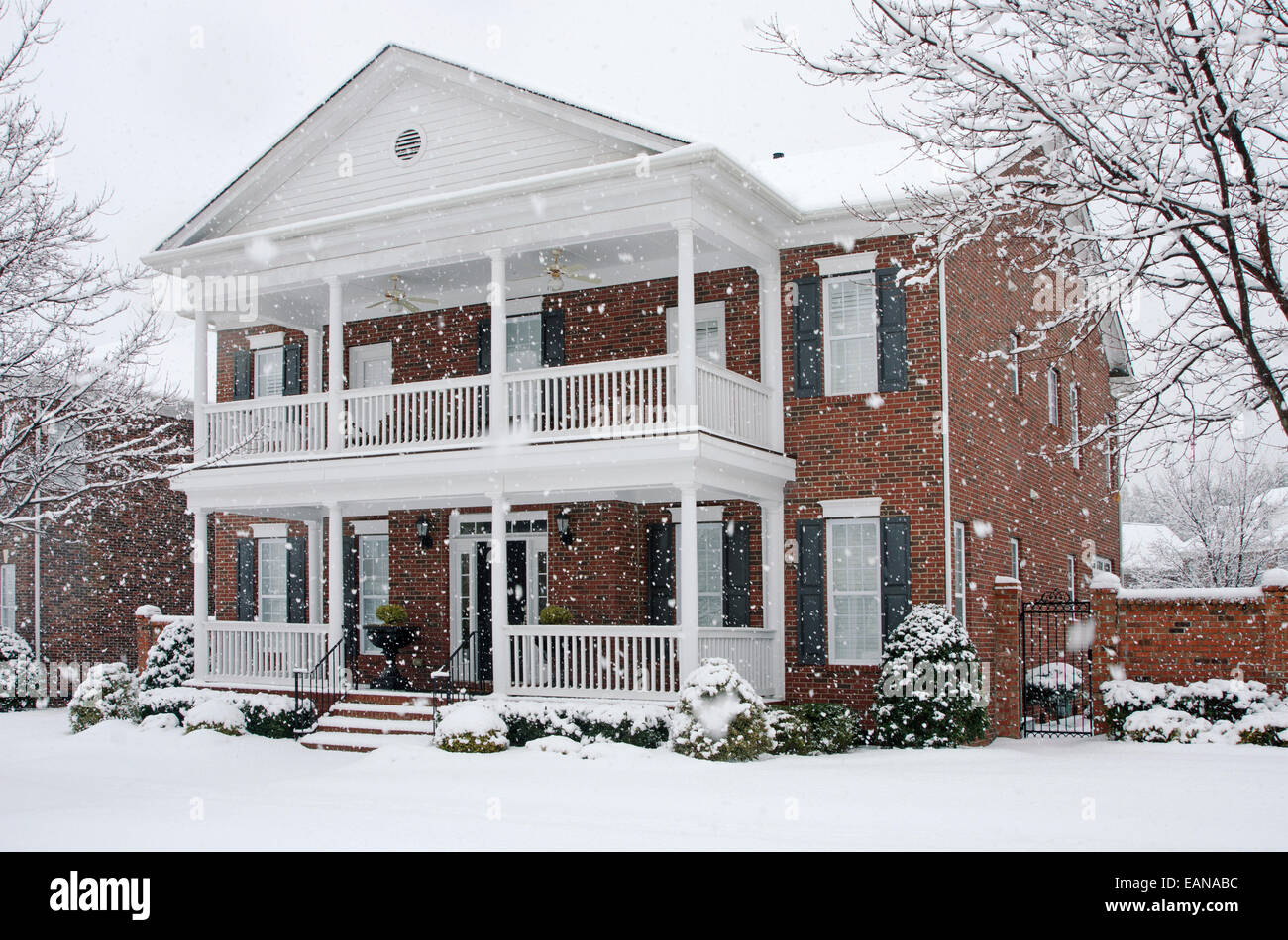 A traditional, brick home is captured during a snow storm in this ...