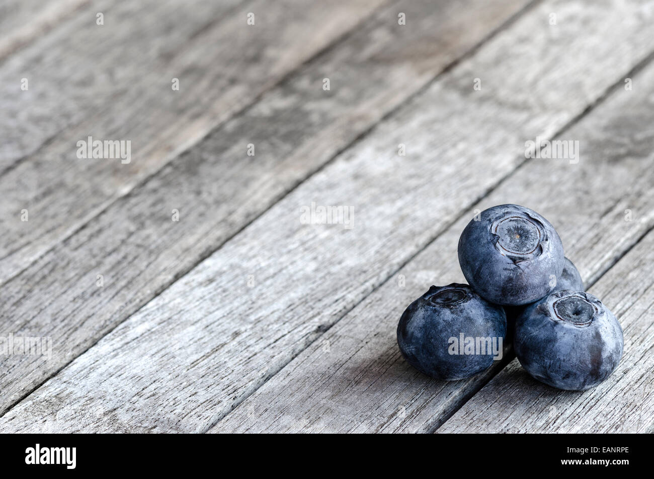Four blueberries on a rustic wooden plank background Stock Photo - Alamy
