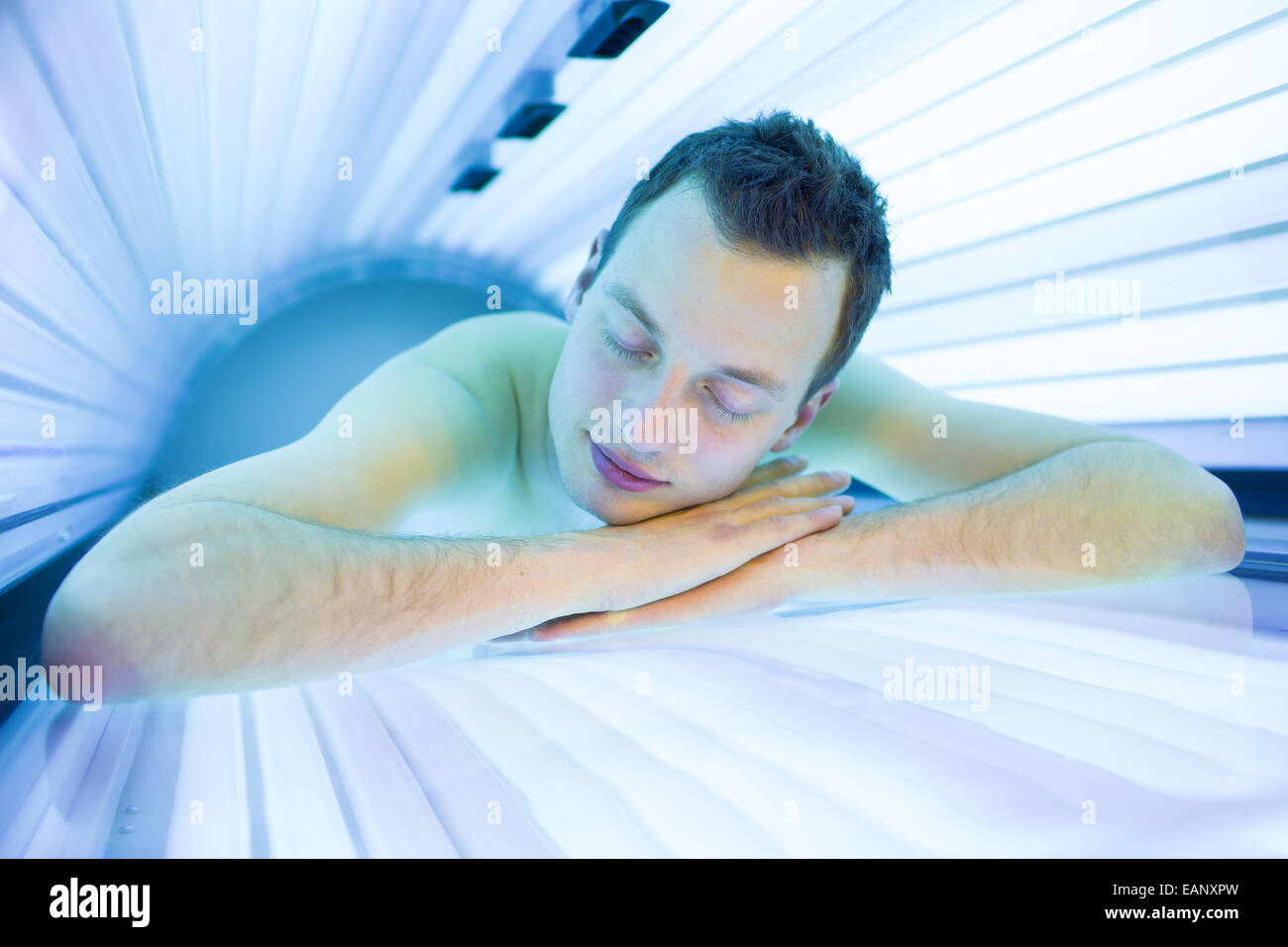 Handsome young man relaxing during a tanning session in a modern ...