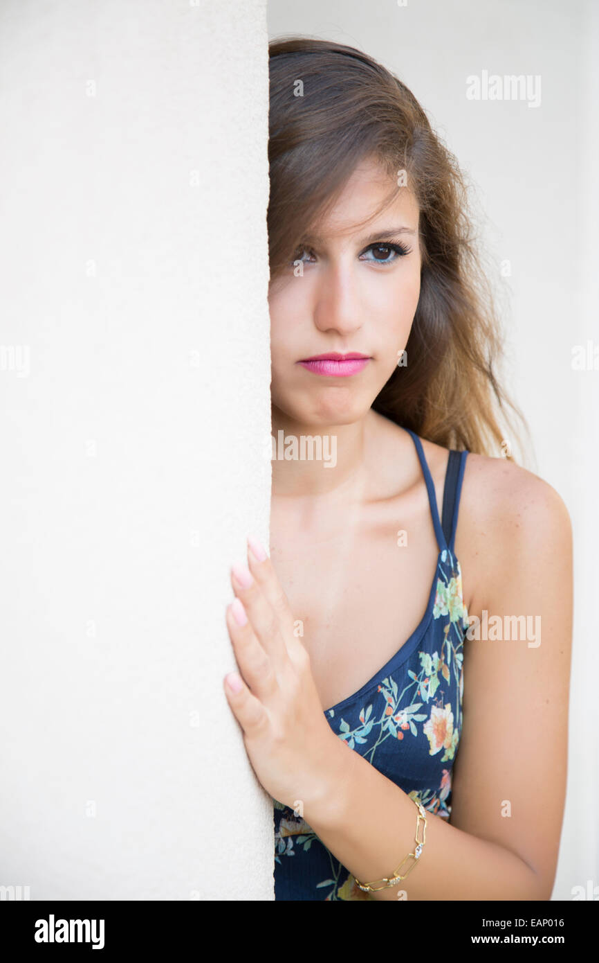 Beautiful young woman peeking behind wall Stock Photo - Alamy