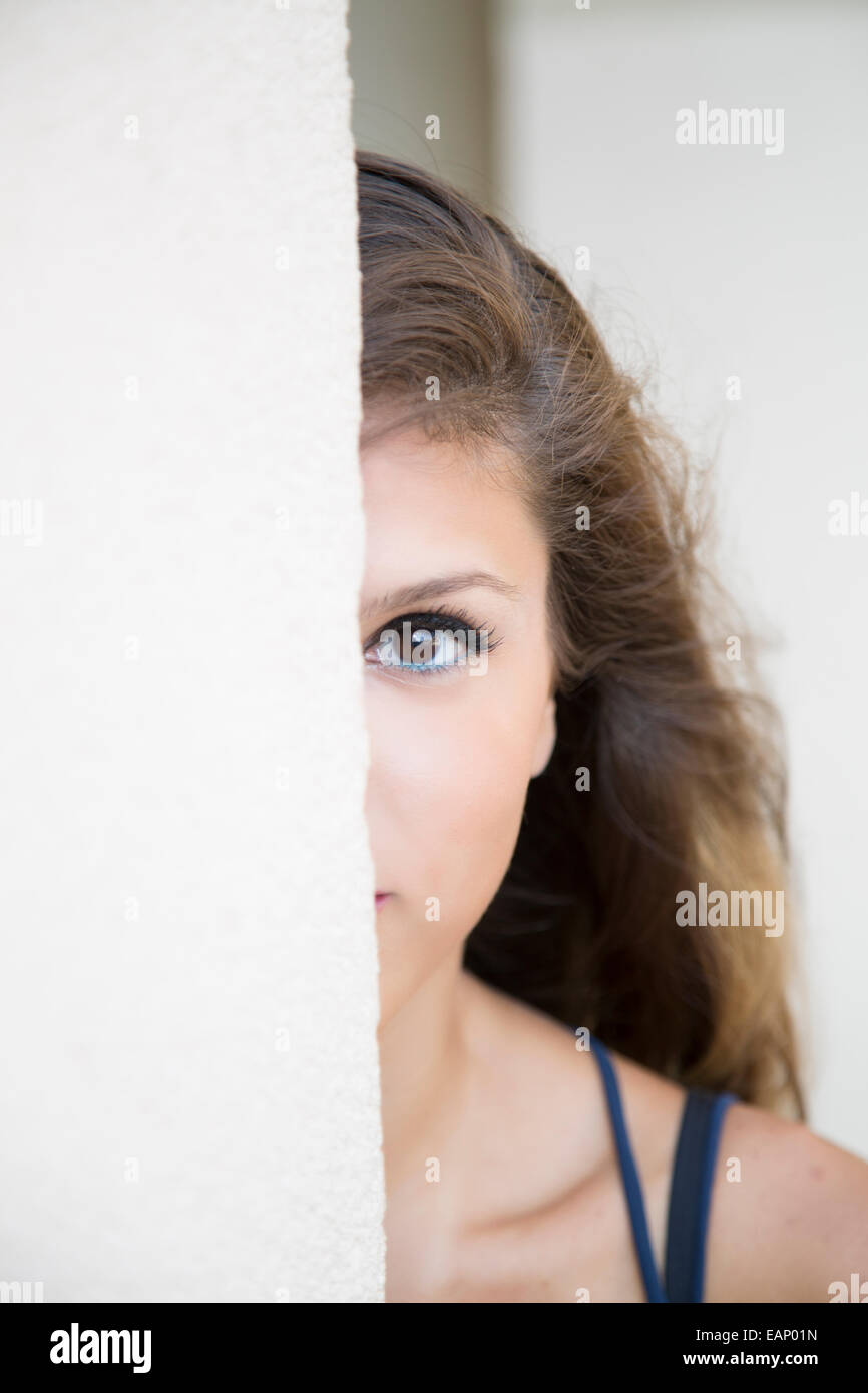 Young woman hiding behind wall Stock Photo - Alamy