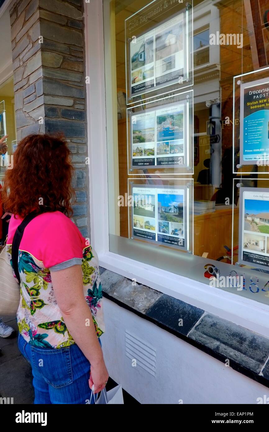 A young adult female looking in the window of an estate agent.Padstow ...