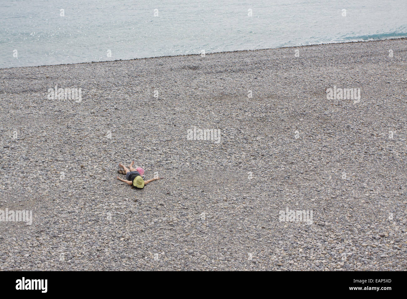 A woman laying on a pebble beach Stock Photo - Alamy