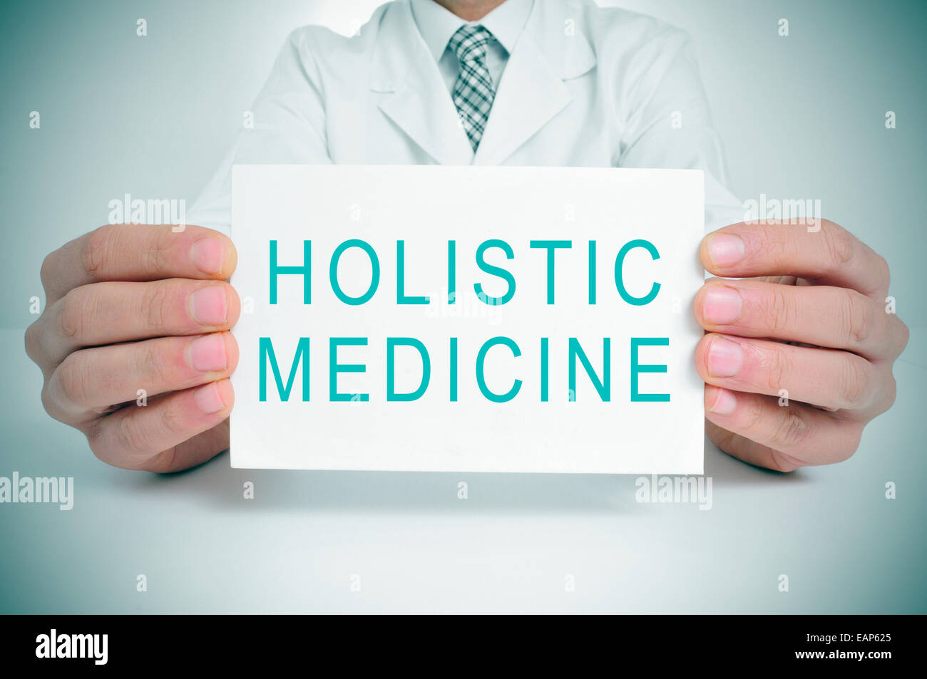 a doctor showing a signboard with the text holistic medicine written in ...