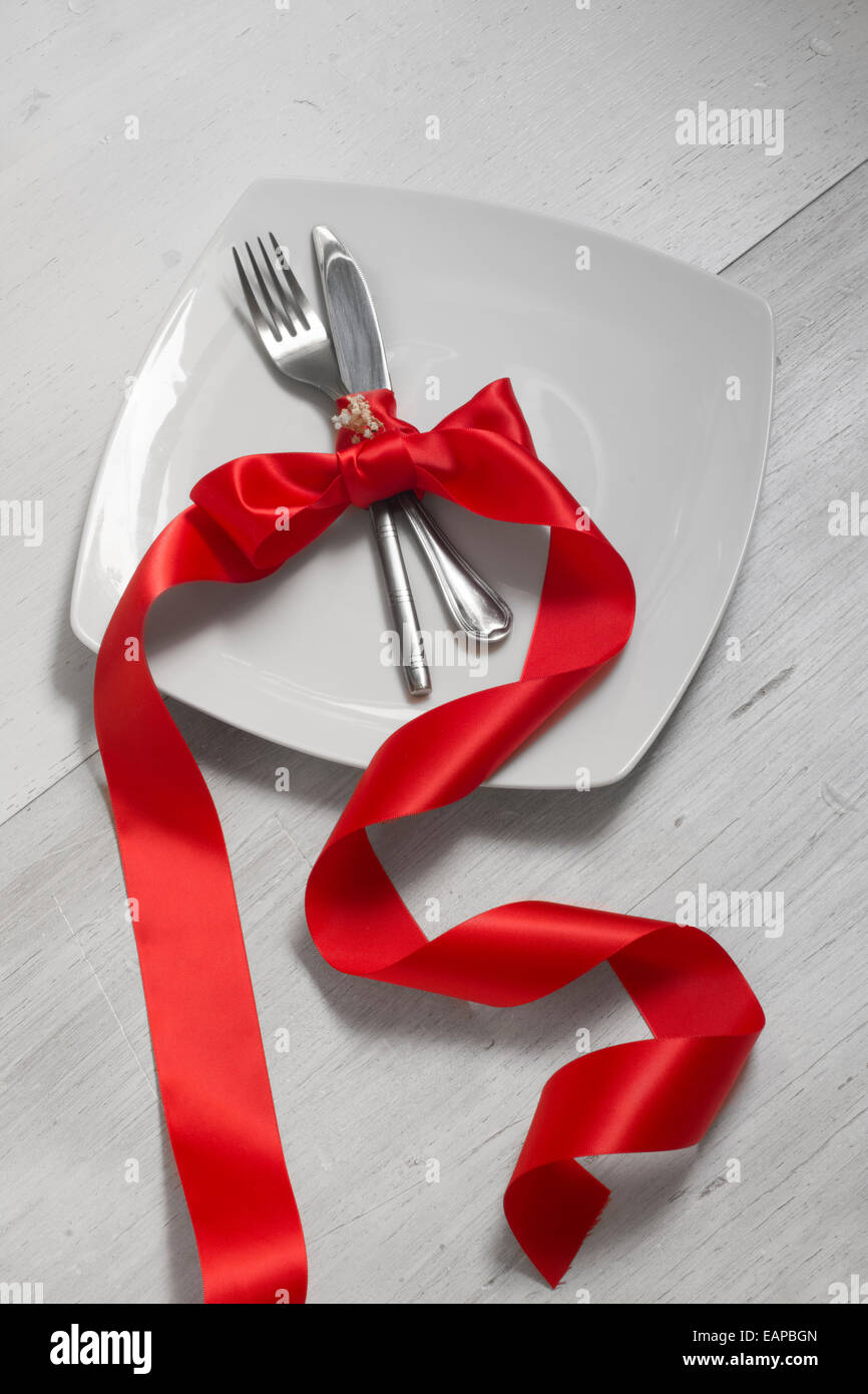 Festive table setting and decoration with red ribbon, on white wood ...