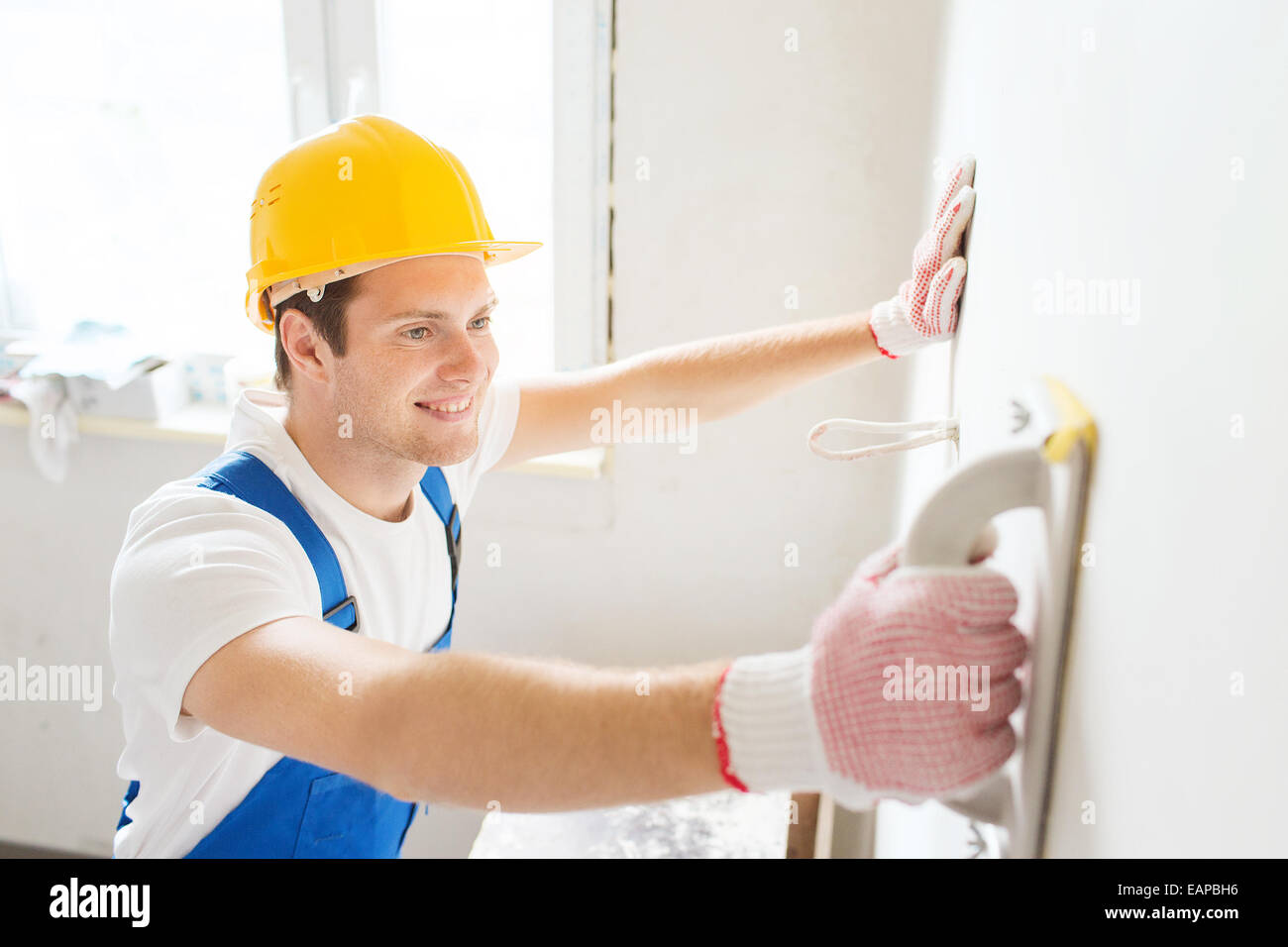 smiling builder with grinding tool indoors Stock Photo - Alamy