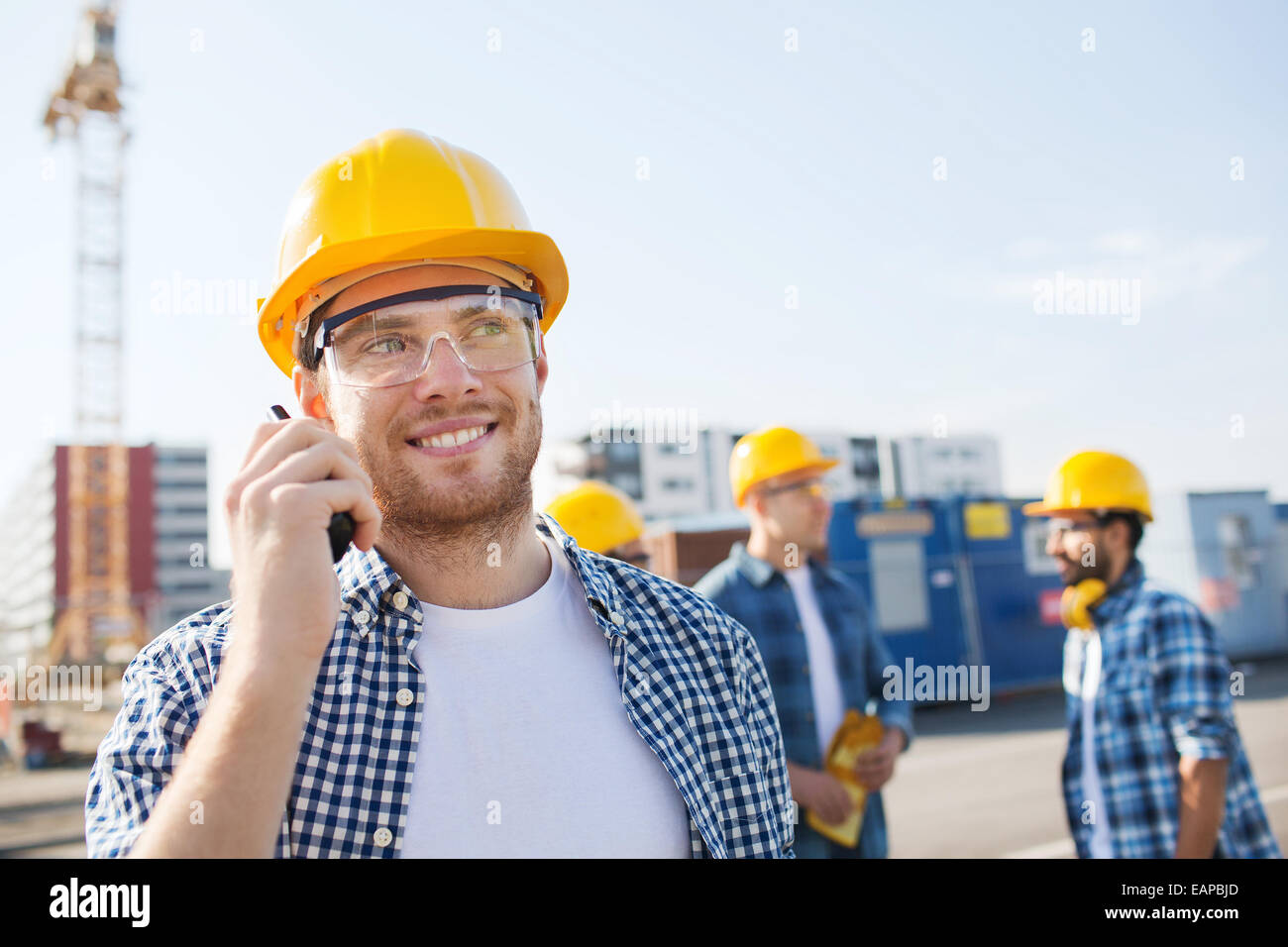 group of smiling builders in hardhats with radio Stock Photo - Alamy