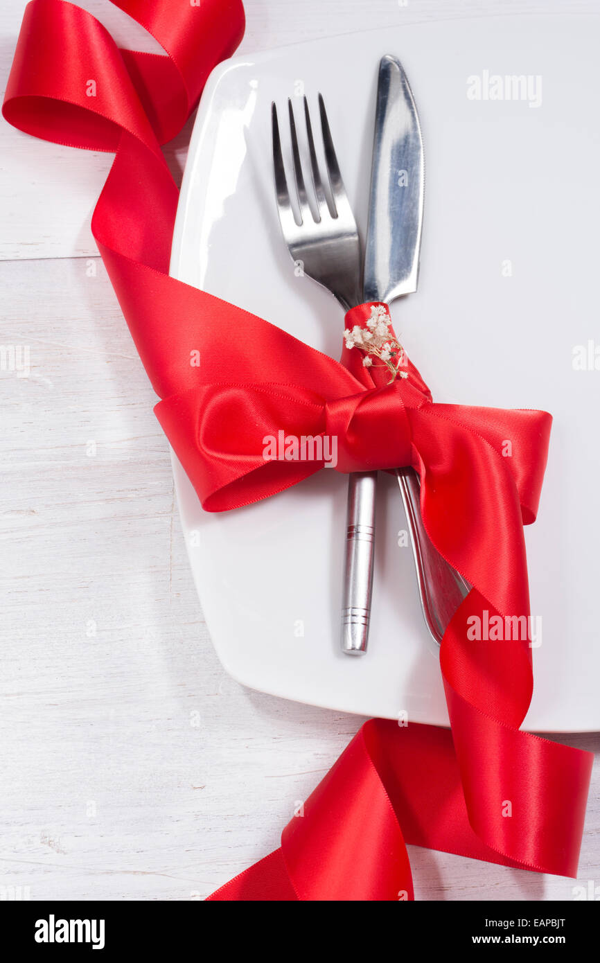Festive table setting and decoration with red ribbon, on white wood ...