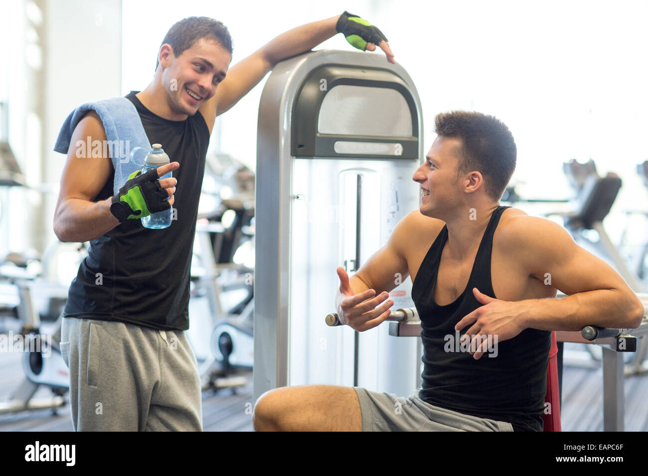 smiling men exercising on gym machine Stock Photo - Alamy