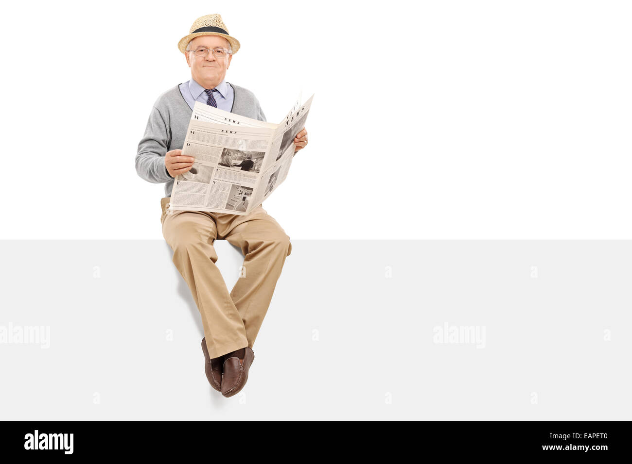Senior holding a newspaper seated on a panel isolated on white ...