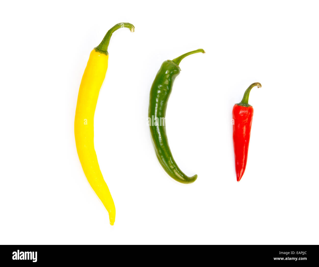 Three peppers in a row in different colors against white background ...
