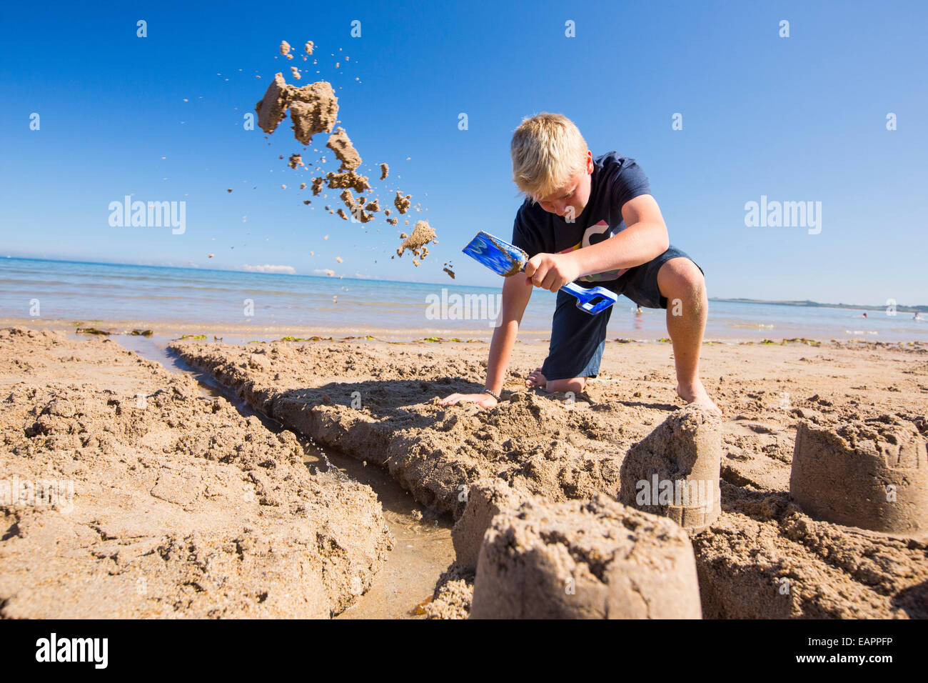 A boy building a sandcastle on Bamburgh Beach, Northumberland, UK Stock ...