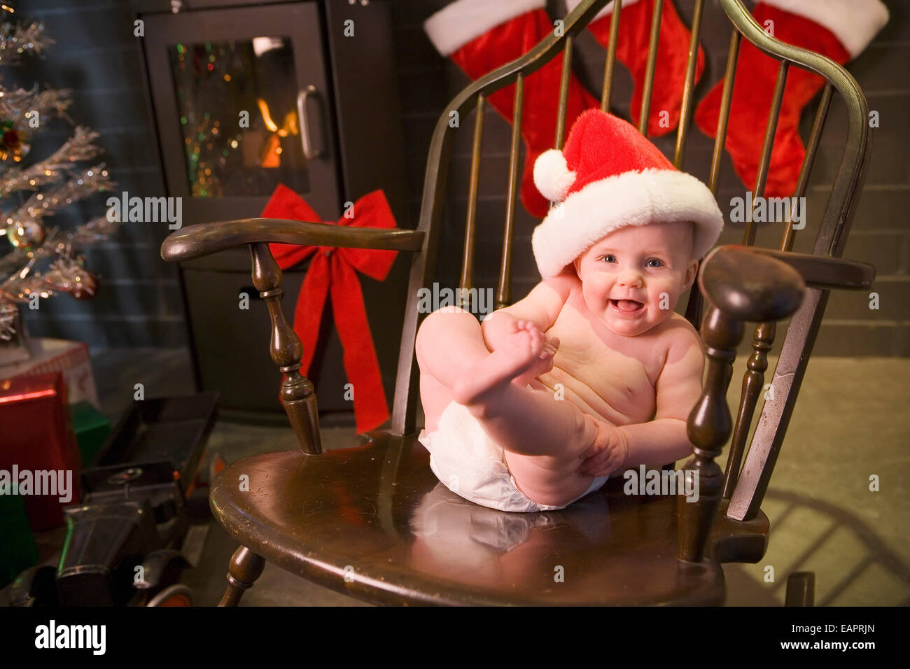 Infant Girl In Diaper Wearing Santa Claus Hat Sitting In Wooden Rocking ...